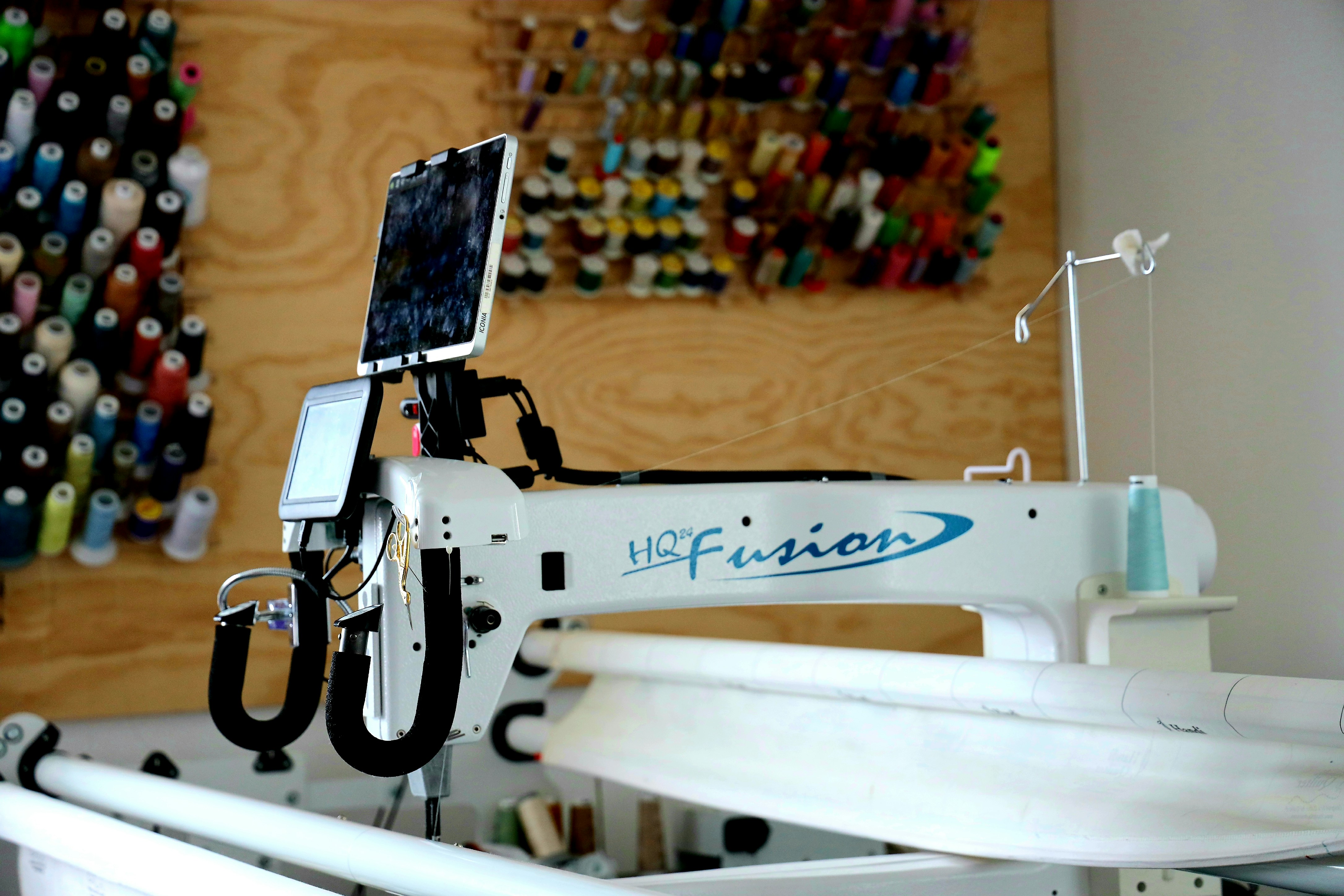High-quality quilting machine with a digital interface, set against a backdrop of colorful thread spools. The setup emphasizes the blend of technology and craft.
