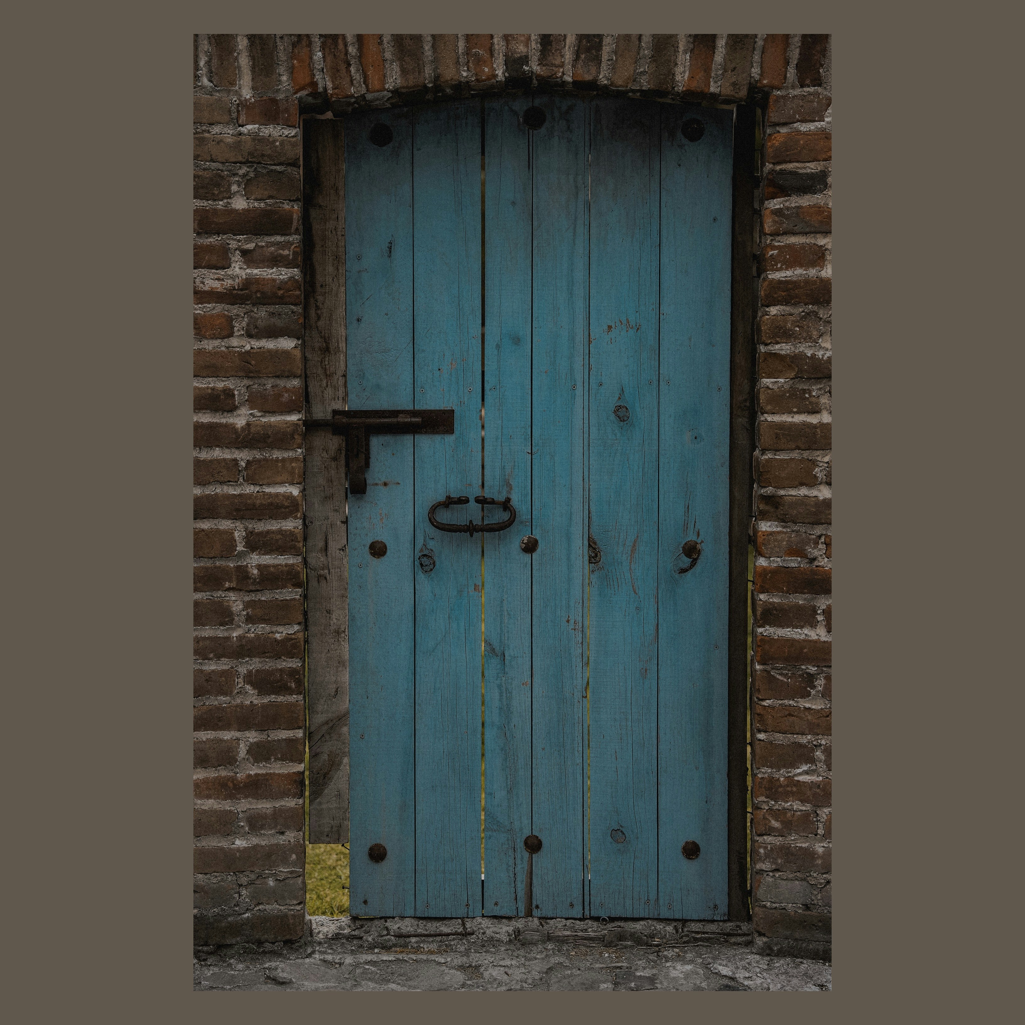 Azure Doorway in a Brick Arch: Timeworn Charm of a Quiet Threshold