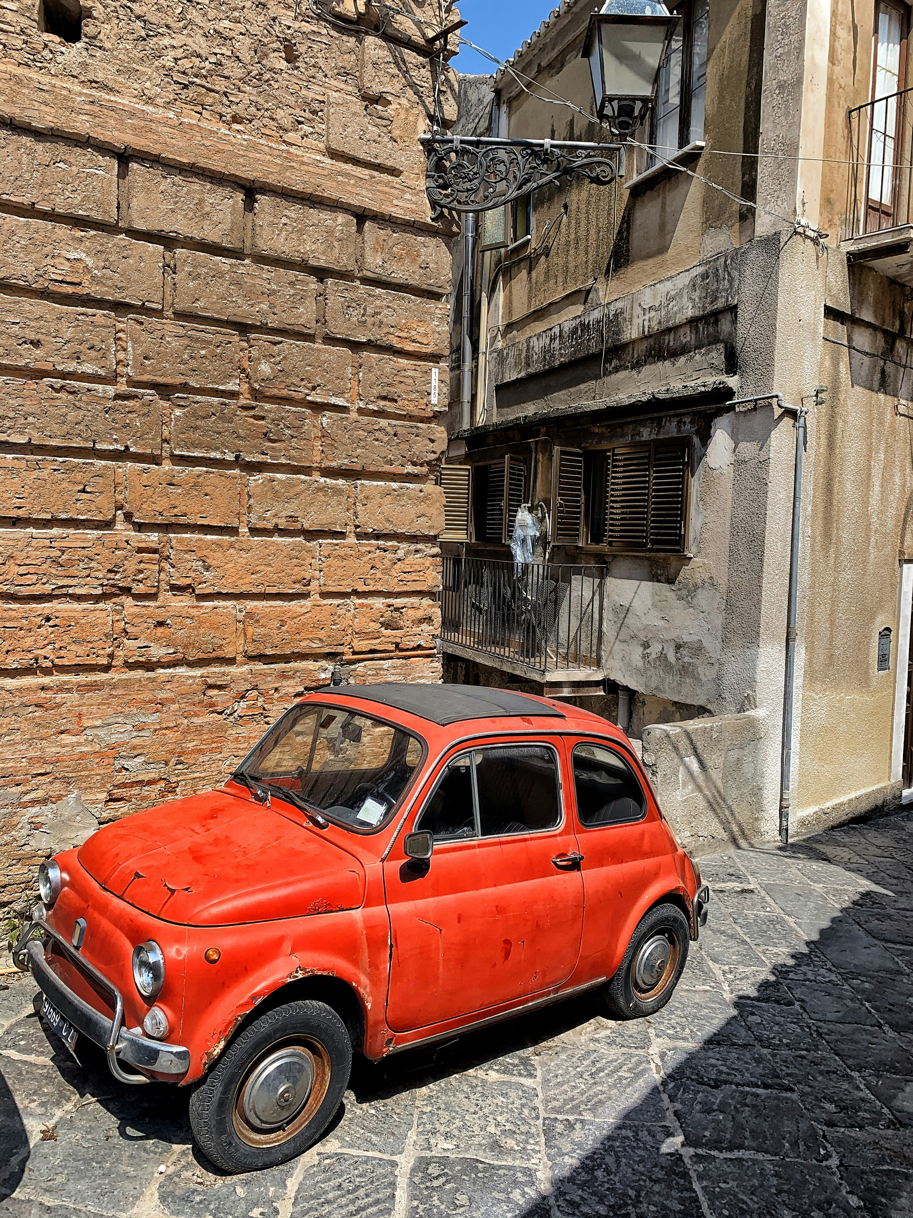 Red volkswagen beetle parked beside brown brick building during daytime ...