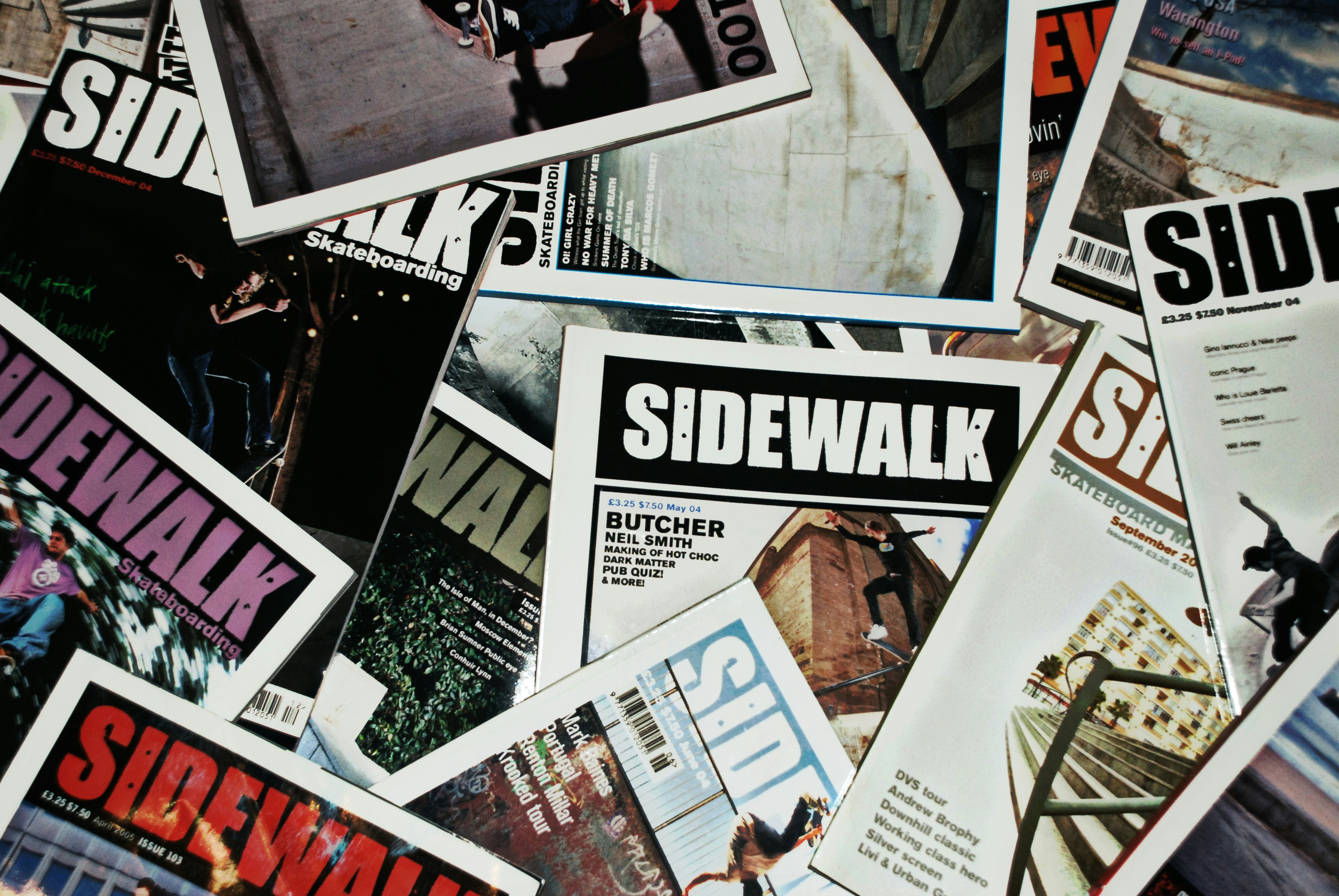 A collection of 'Sidewalk' skateboarding magazines scattered on a surface, showcasing various covers and vibrant imagery. The layout highlights the diversity of skateboarding styles and personalities.