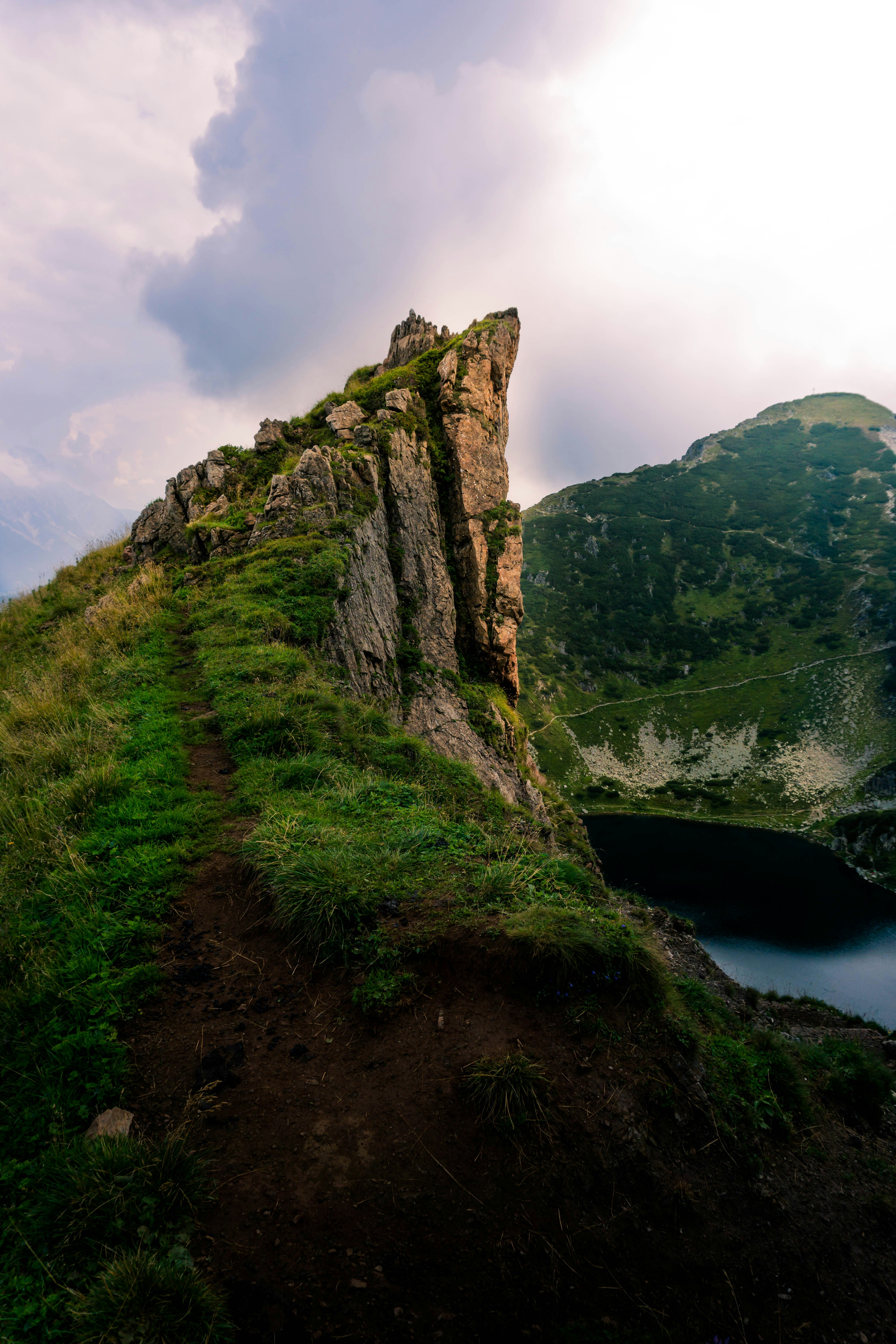 Stone Spire at the Ridge's Edge Over a Quiet Crater Lake