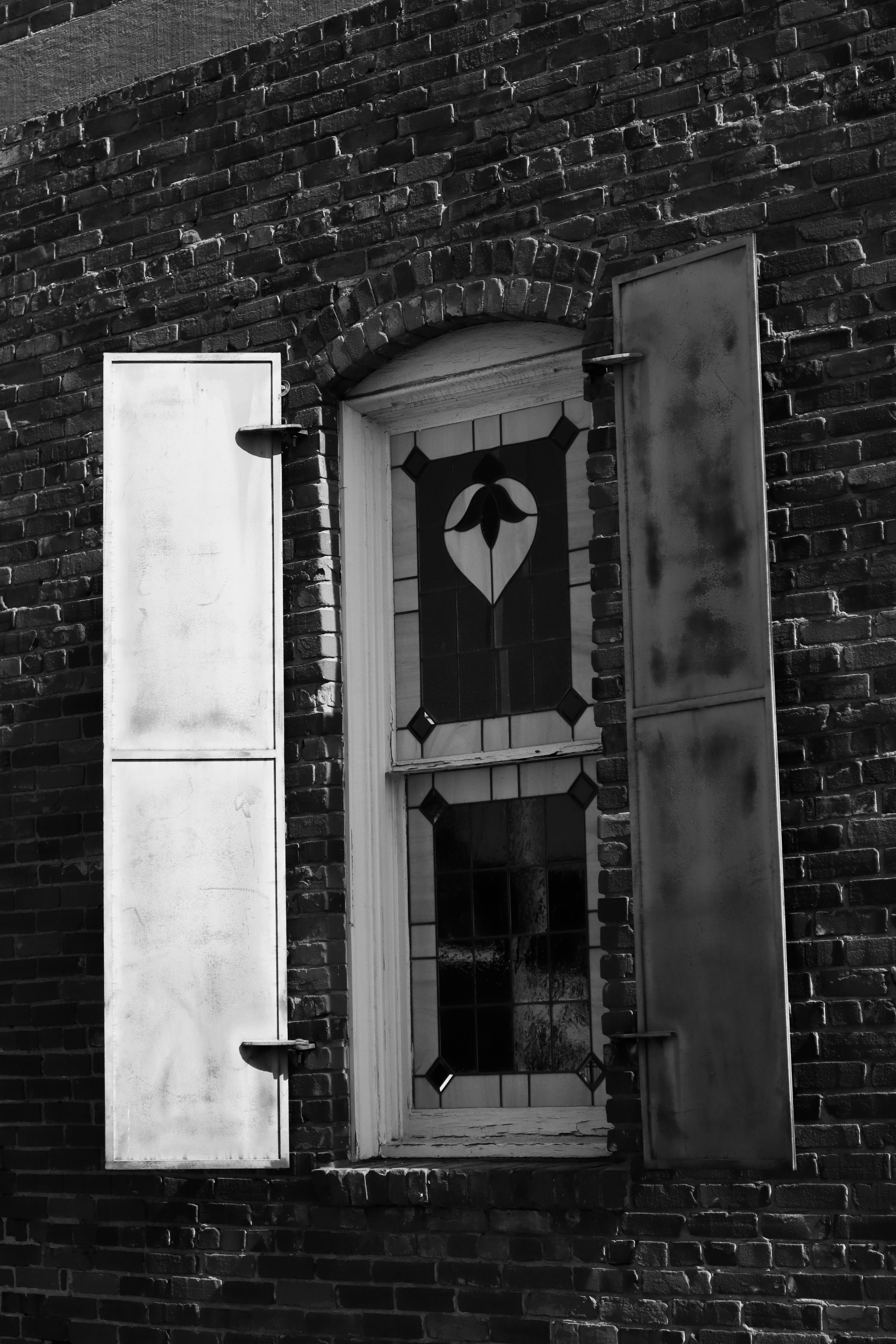 Stained Heart: A Brick-Framed Window with Shuttered Silence