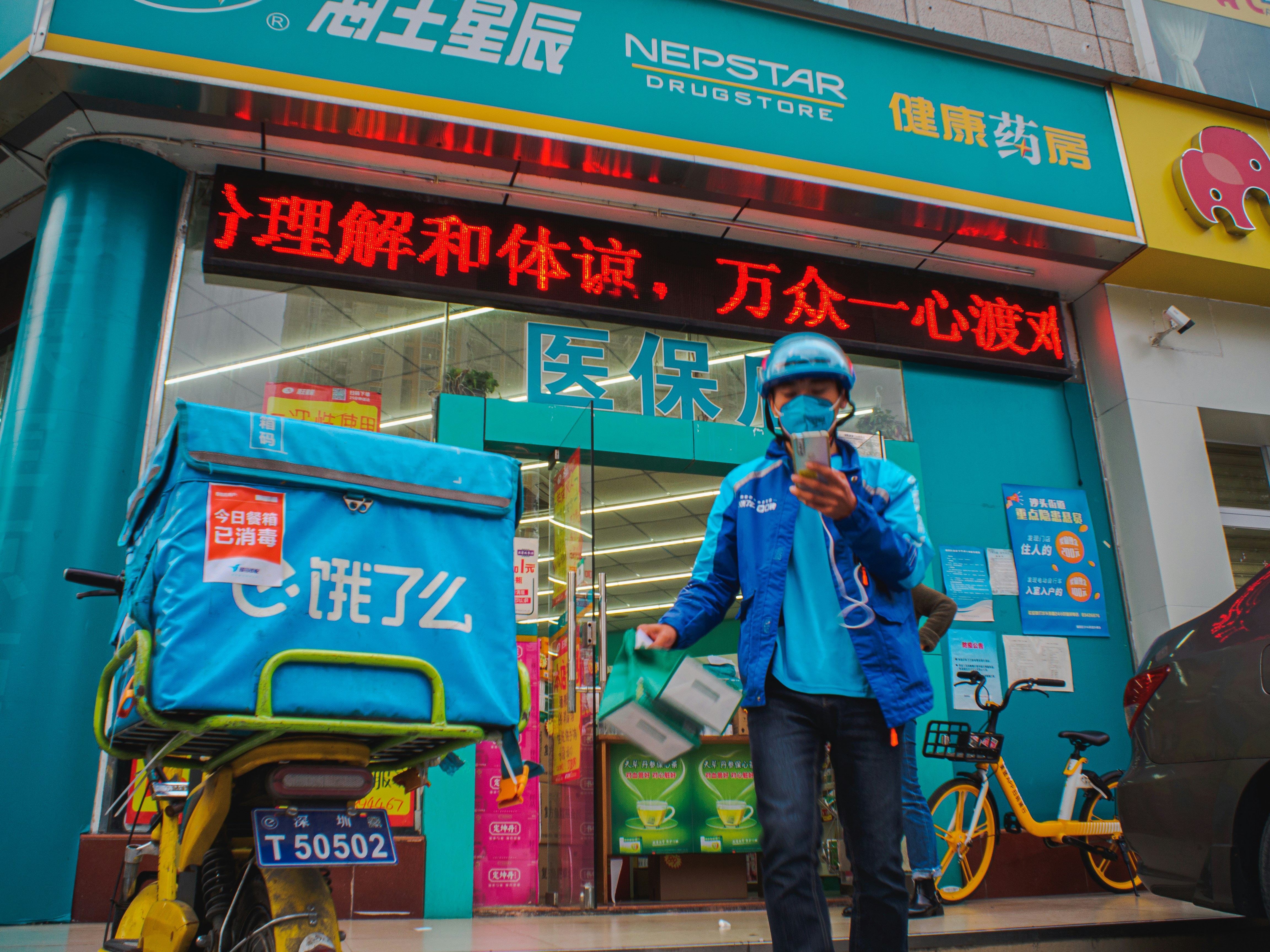 Blue Courier at Neon Pharmacy: Street-Level Delivery Under Fluorescent Glow