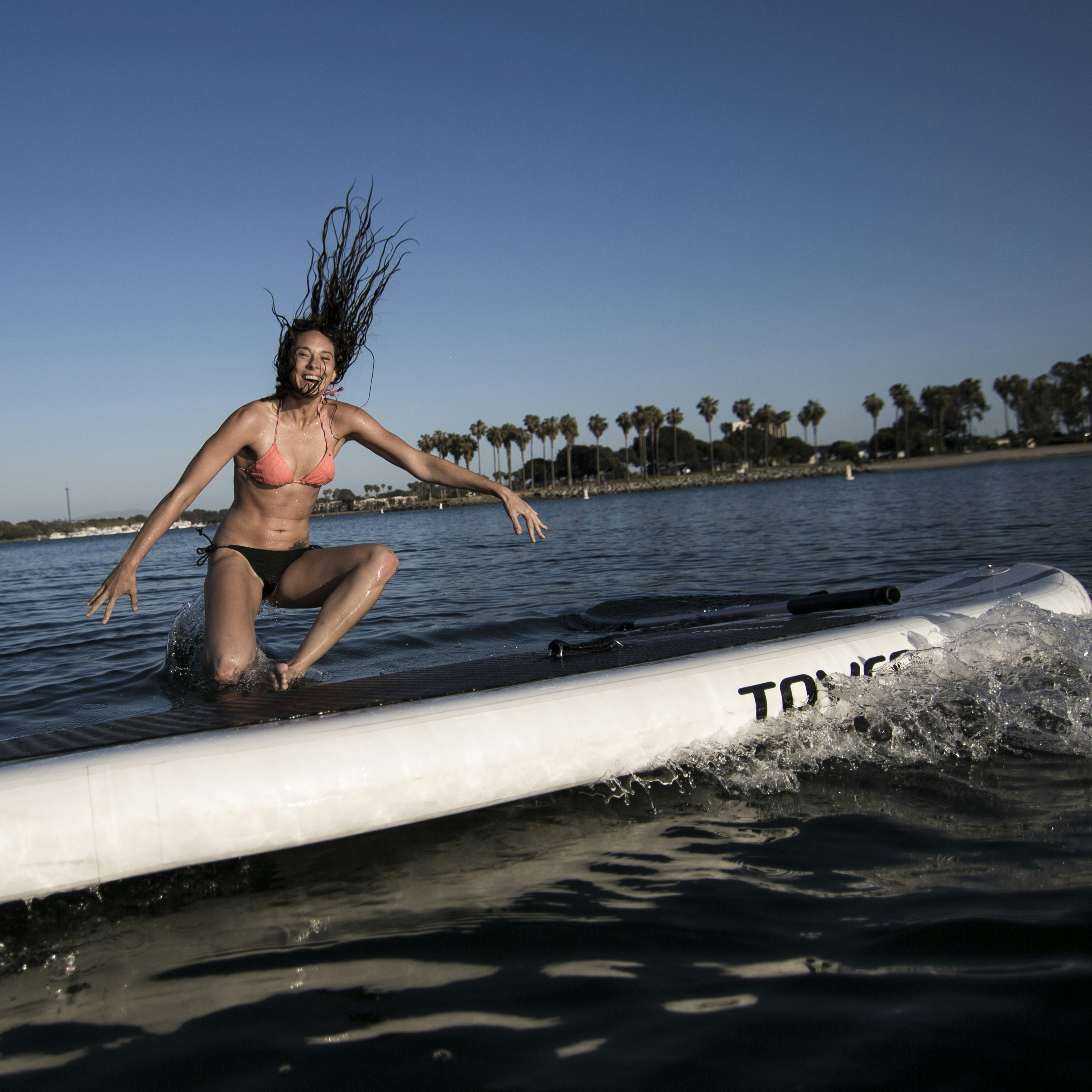 Laughter at Sea: A Surfer’s Jump from a White Waterboard
