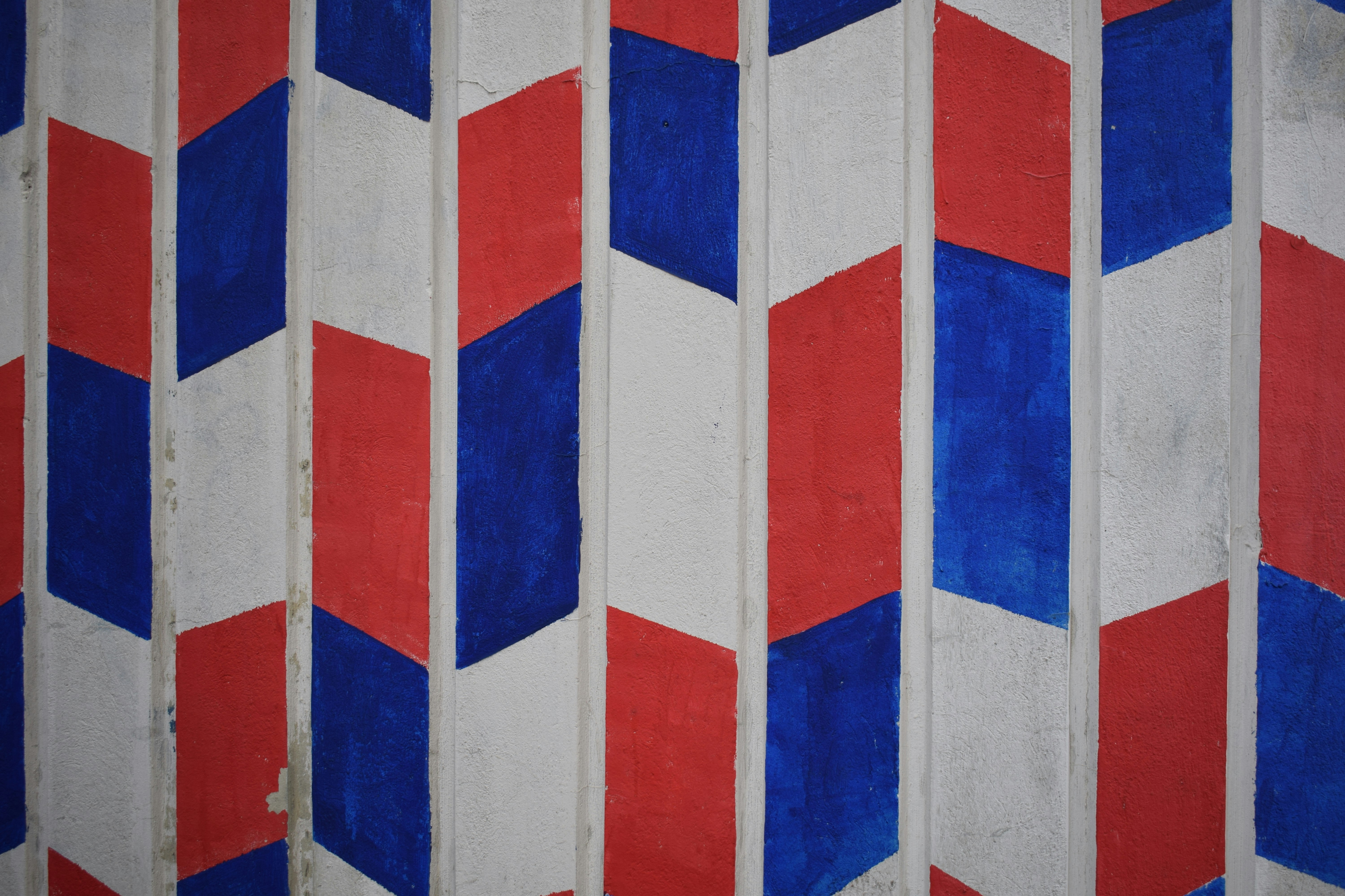 Chevron Cadence: Red and Blue Stripes on Grey Concrete Panels