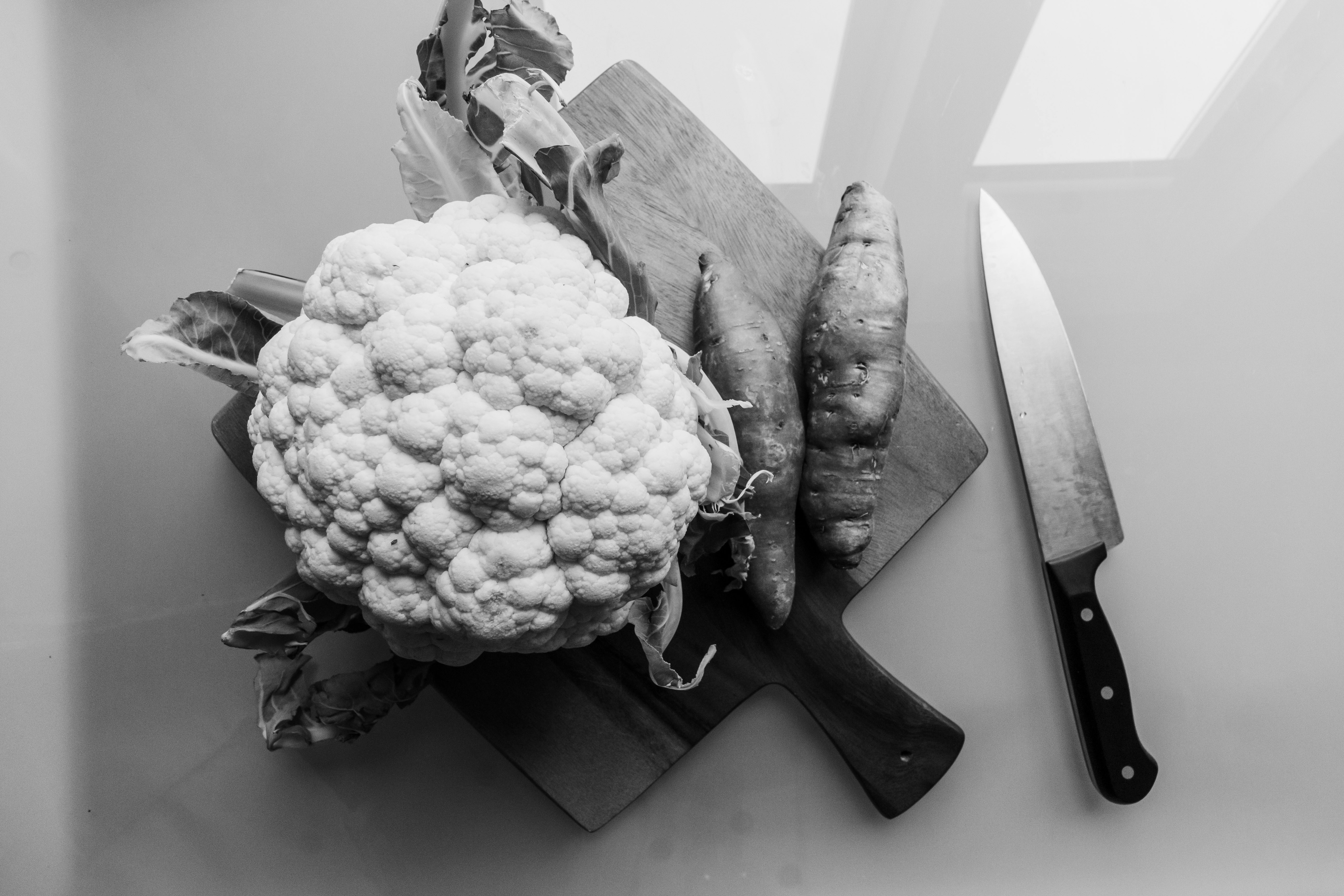 Monochrome Crown: Cauliflower, carrot, and cleaver on a cutting board