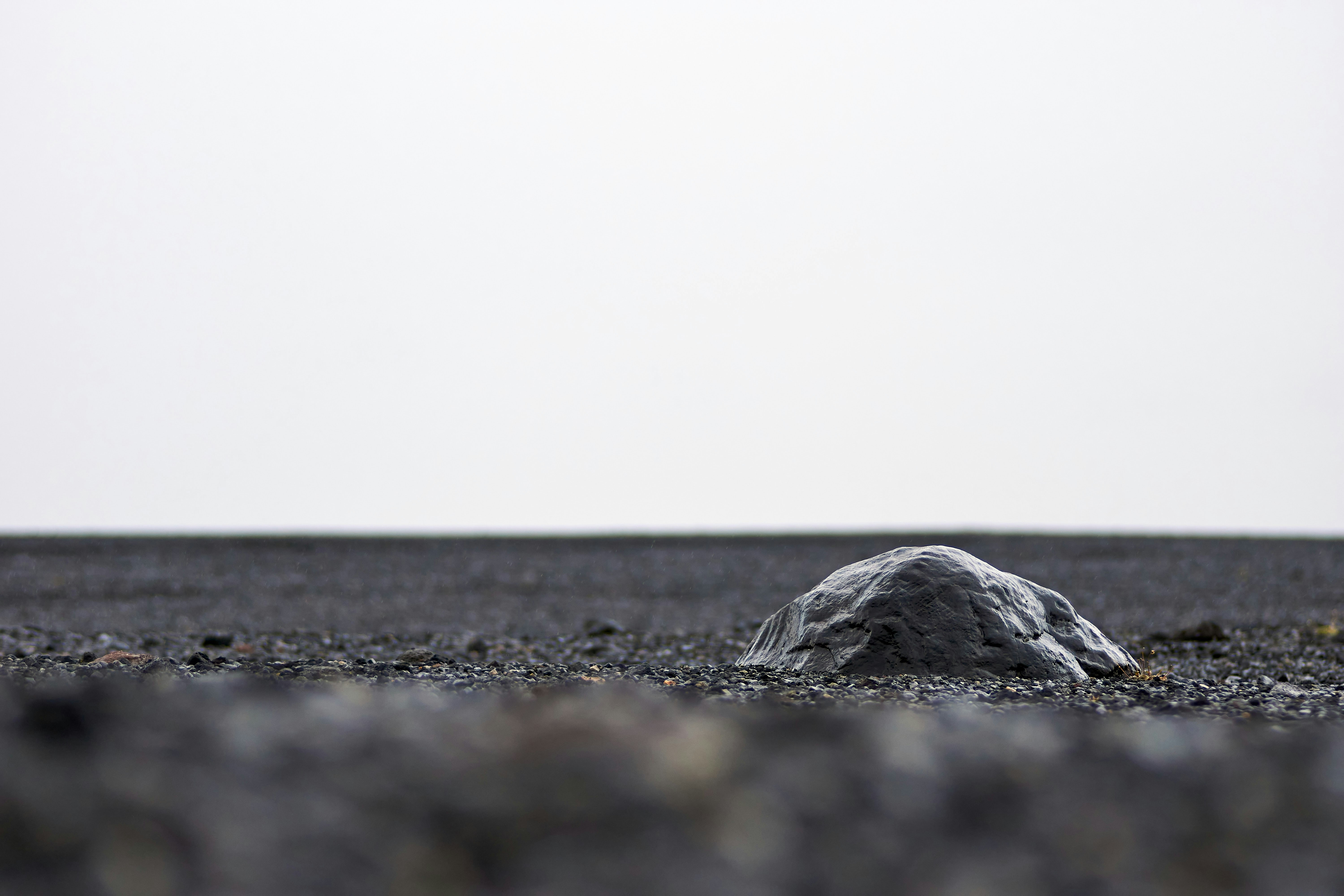Lone Rock on a Quiet Shore Under a Bleached Sky