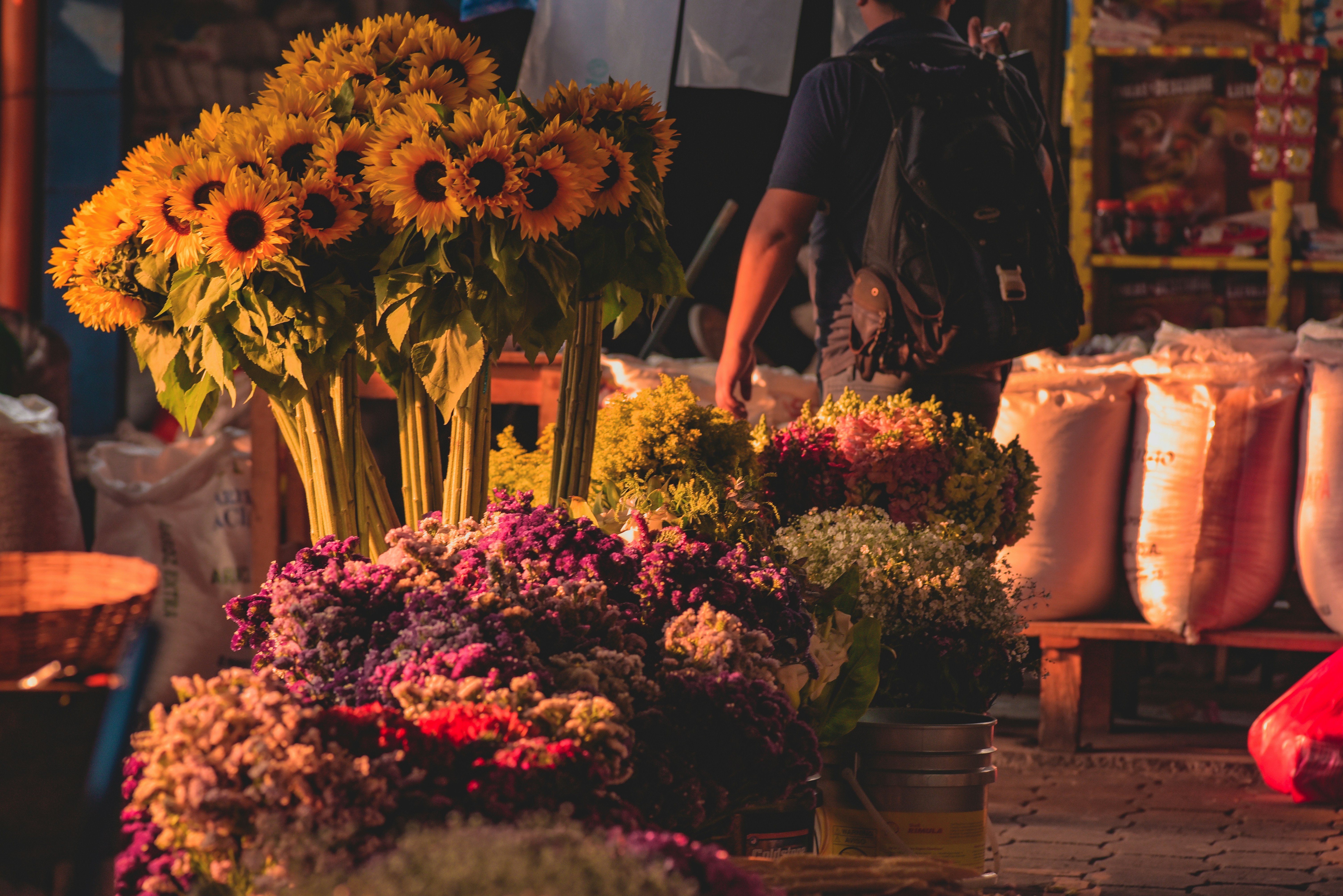 A vibrant display of sunflowers and assorted flowers at a bustling market, capturing the essence of local commerce and nature's beauty.