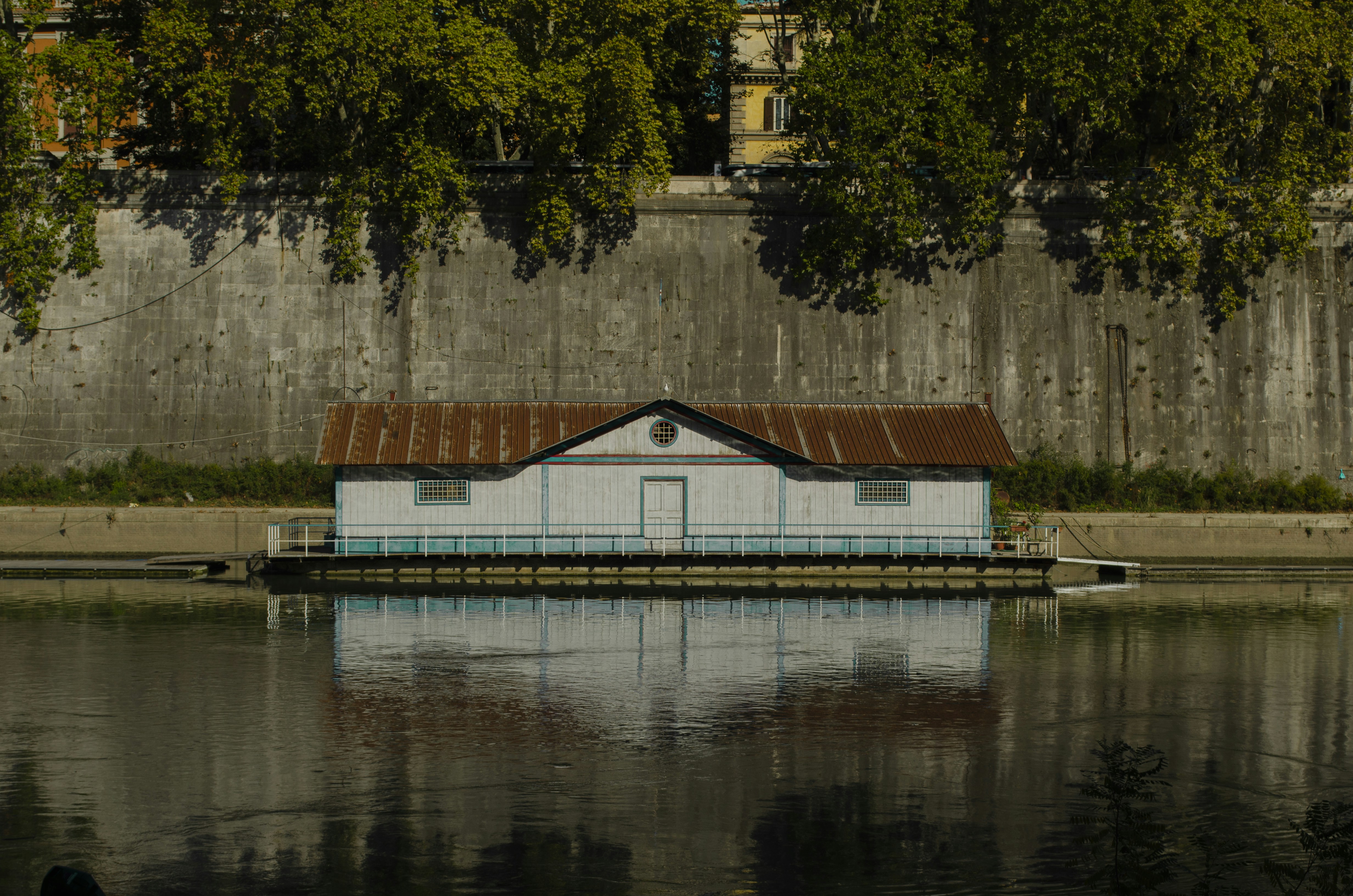 Symmetry by the Water: White Boathouse with Rust Roof