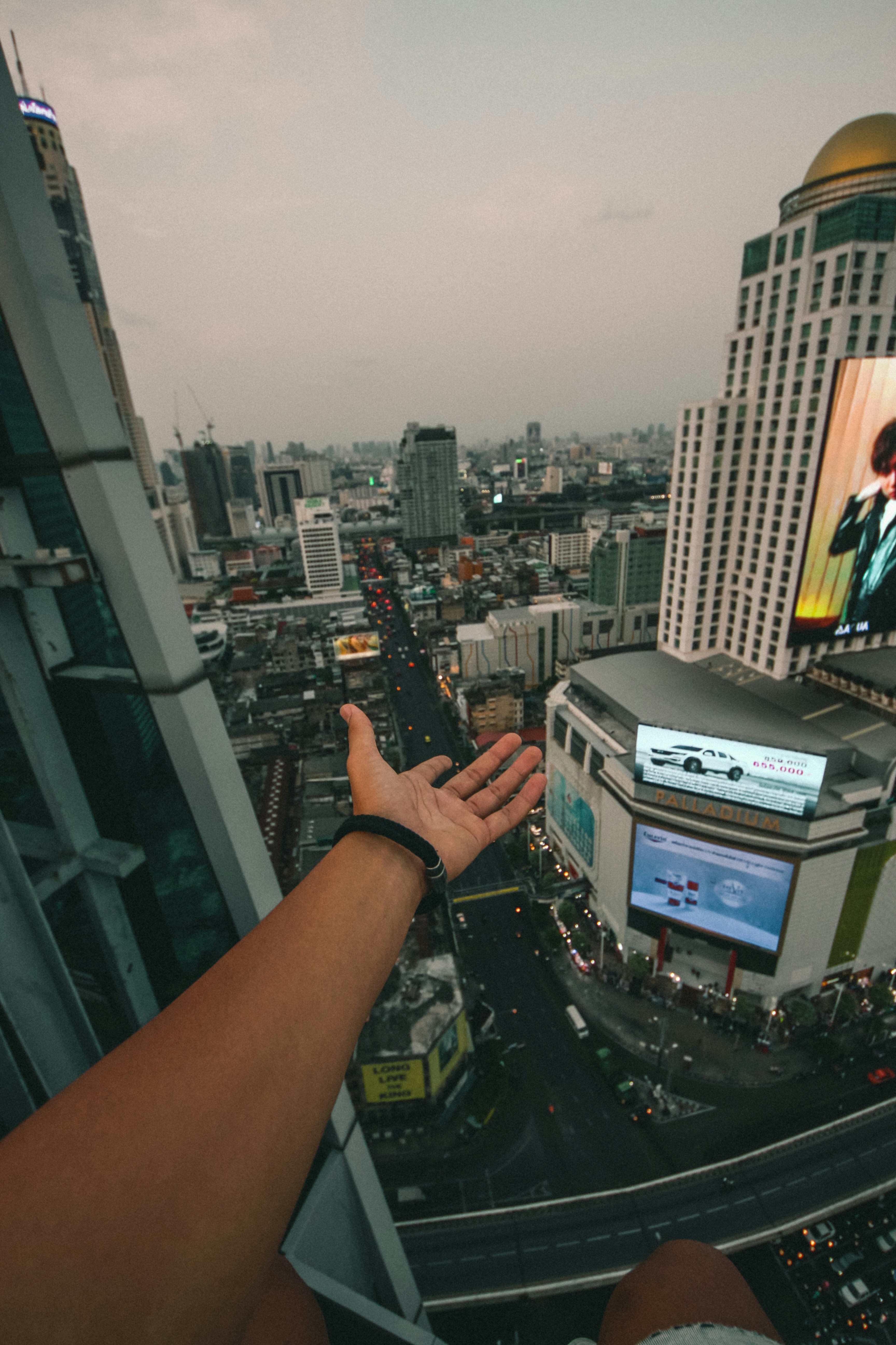 First-Person Rooftop Reach Over a Bustling Downtown