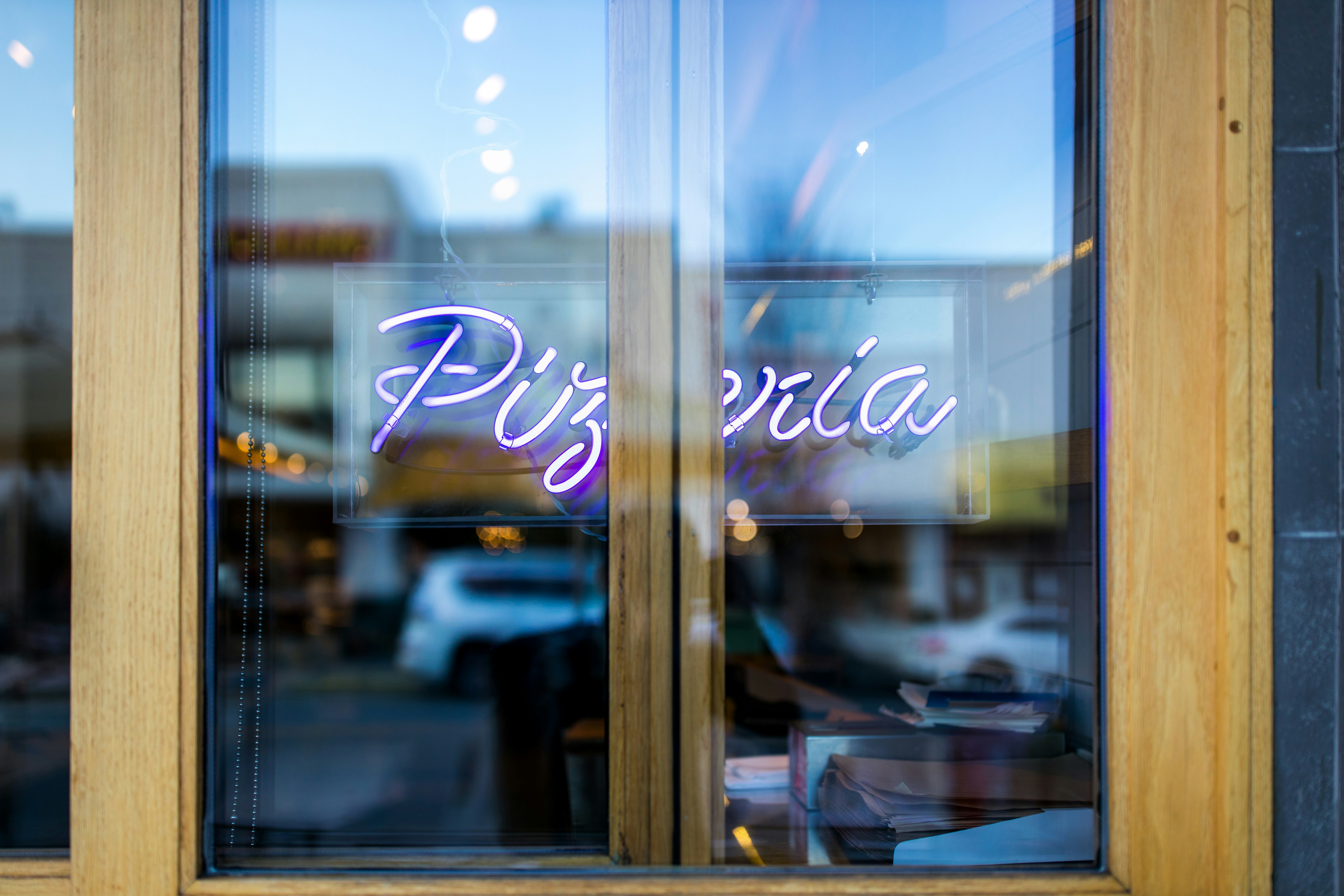 Neon Pizzeria Glow Behind a Wooden Window Frame