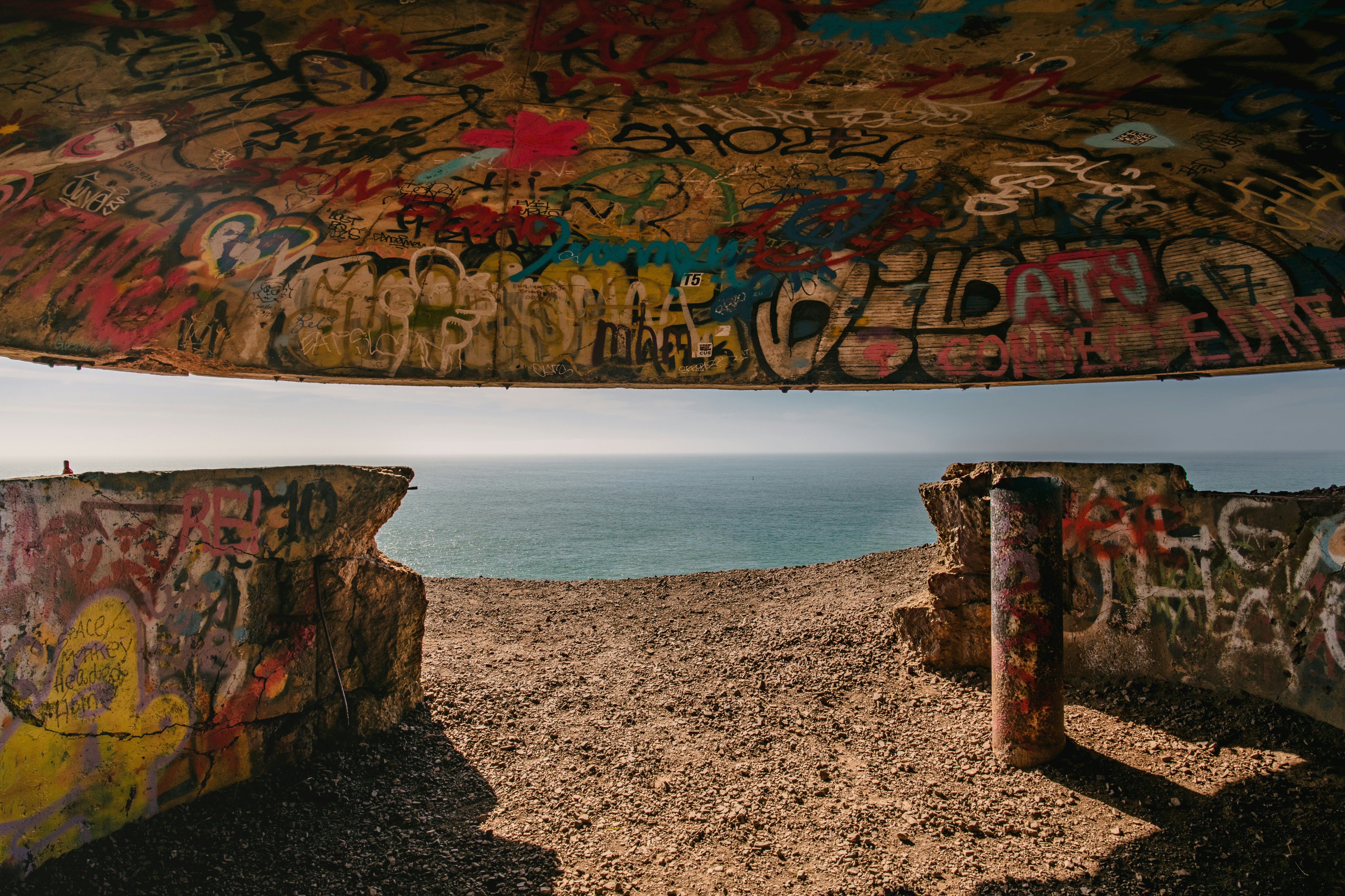 Between Graffiti and Sea: A Pebble Path Through a Painted Gate