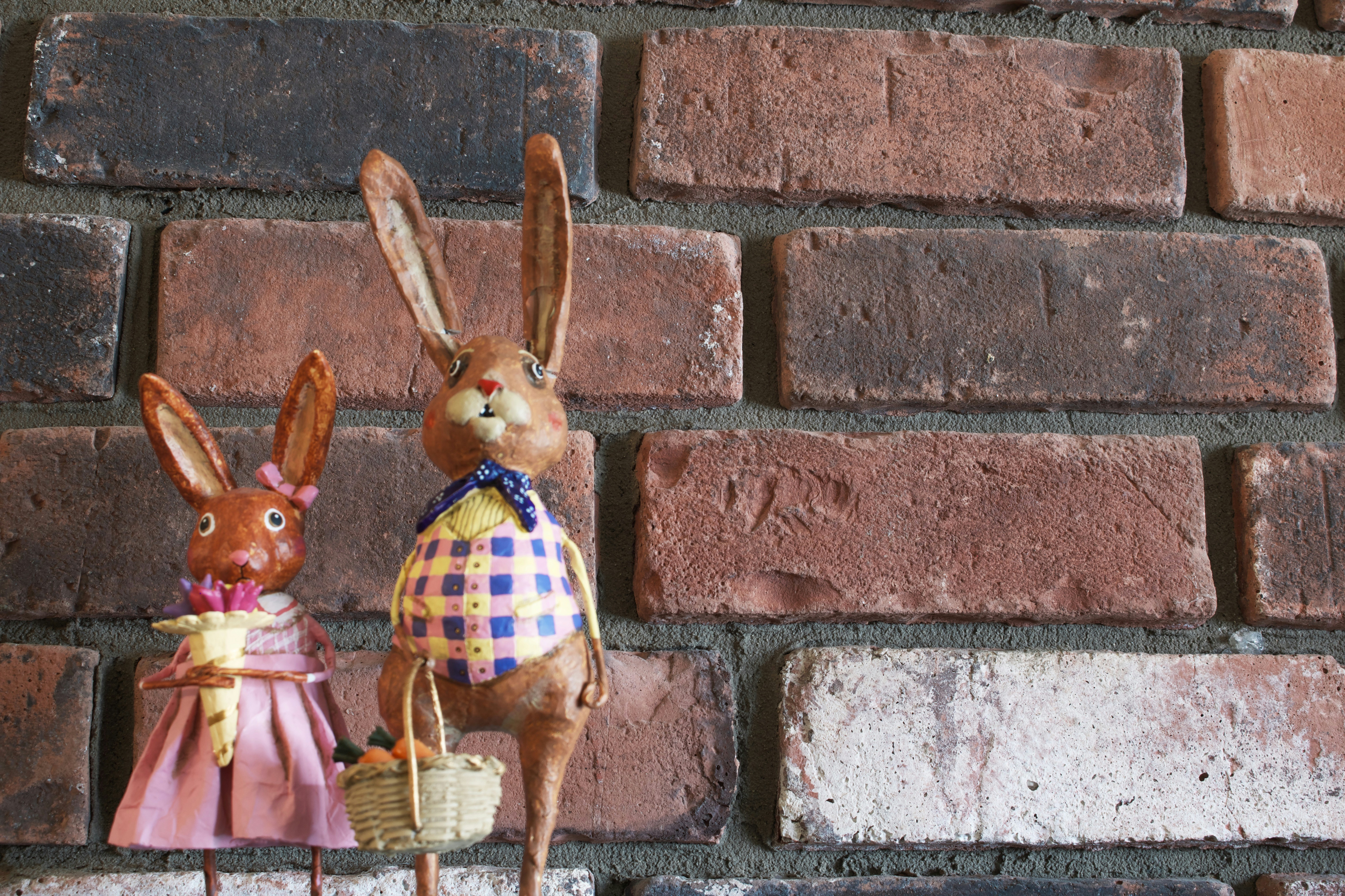 Two Easter Bunny Figurines Stand Guard Against Weathered Brick