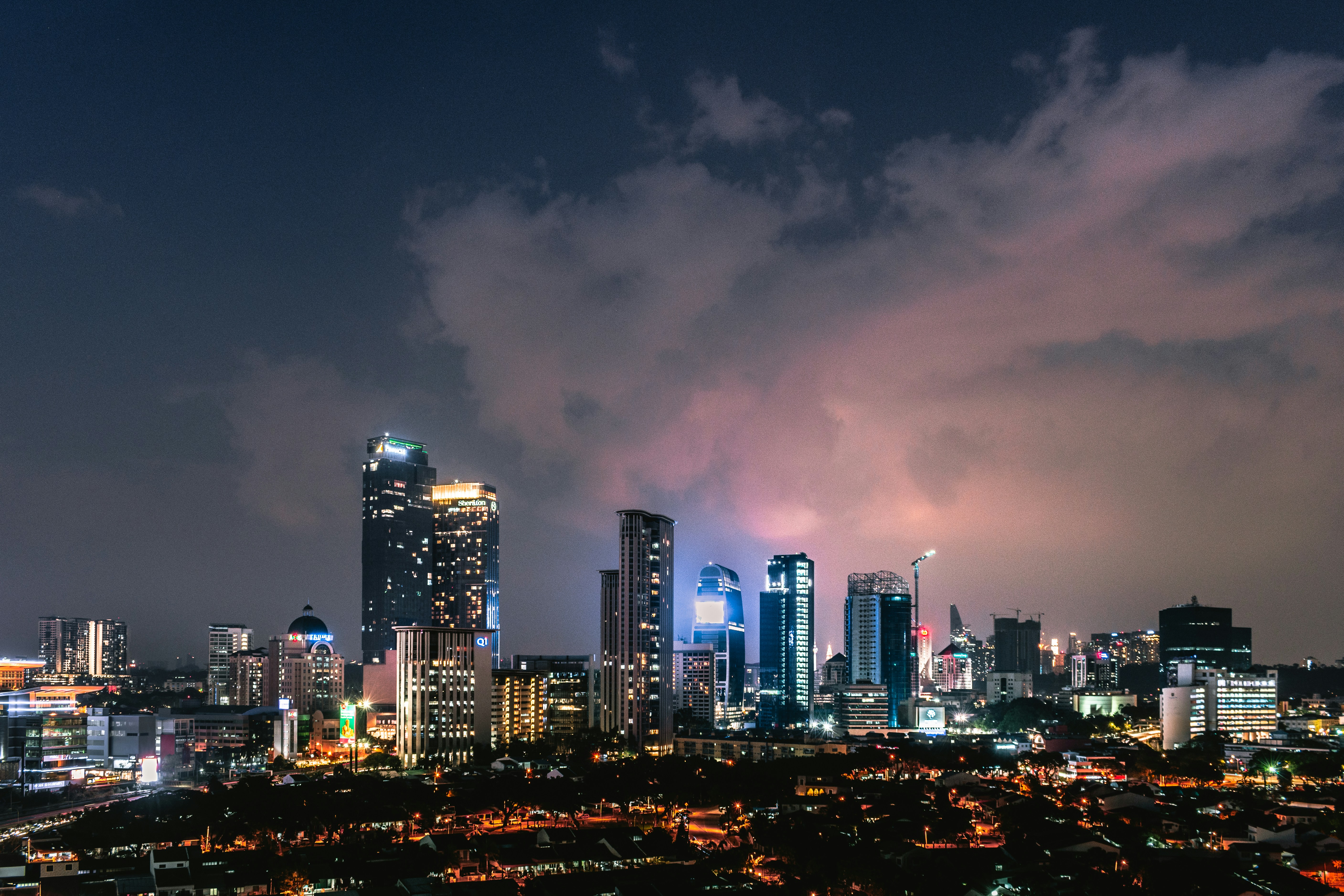 Kuala Lumpur skyline illuminated against a dramatic night sky with vibrant city lights.