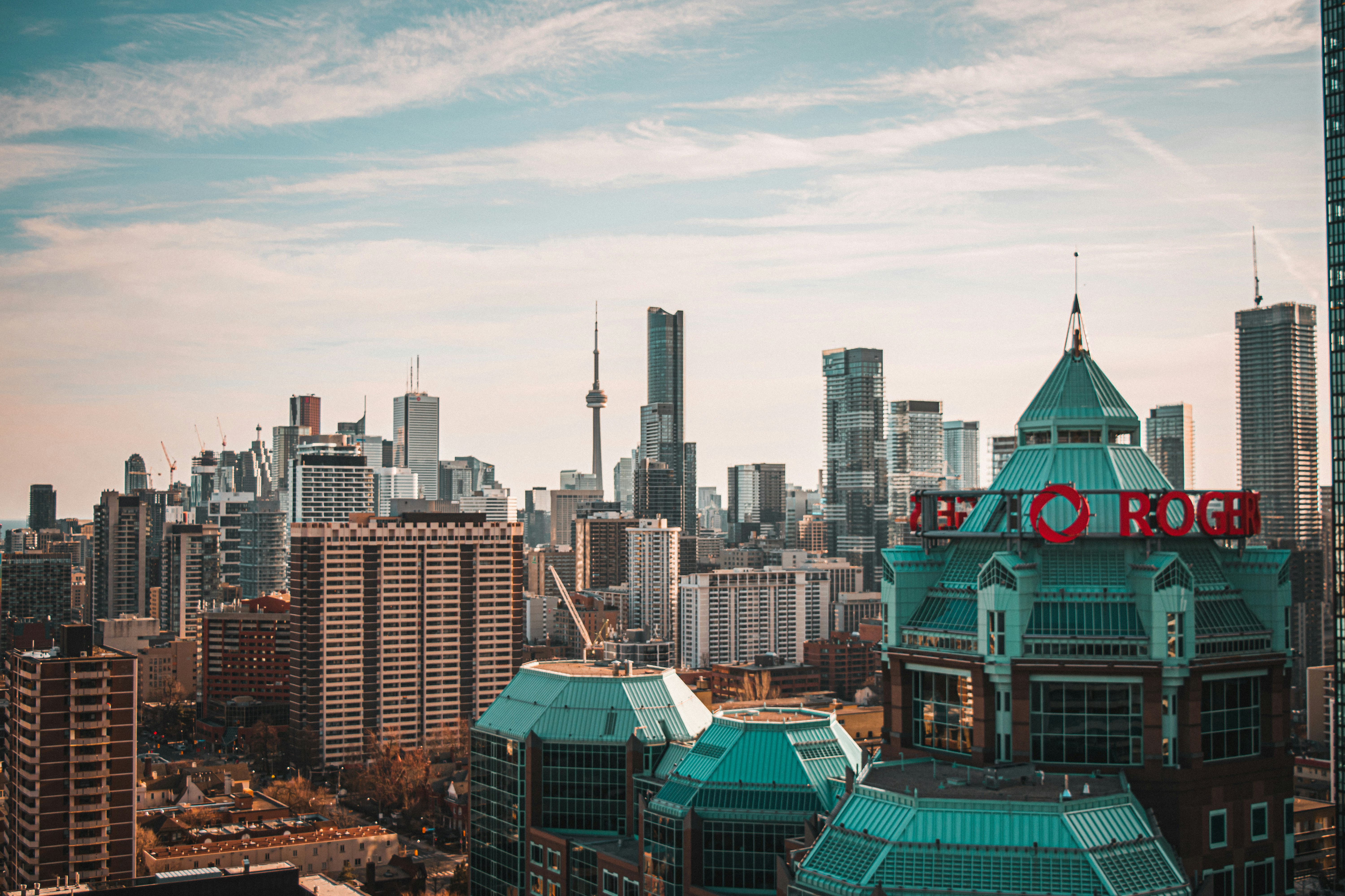 Toronto skyline with CN Tower and historic building under a partly cloudy sky.