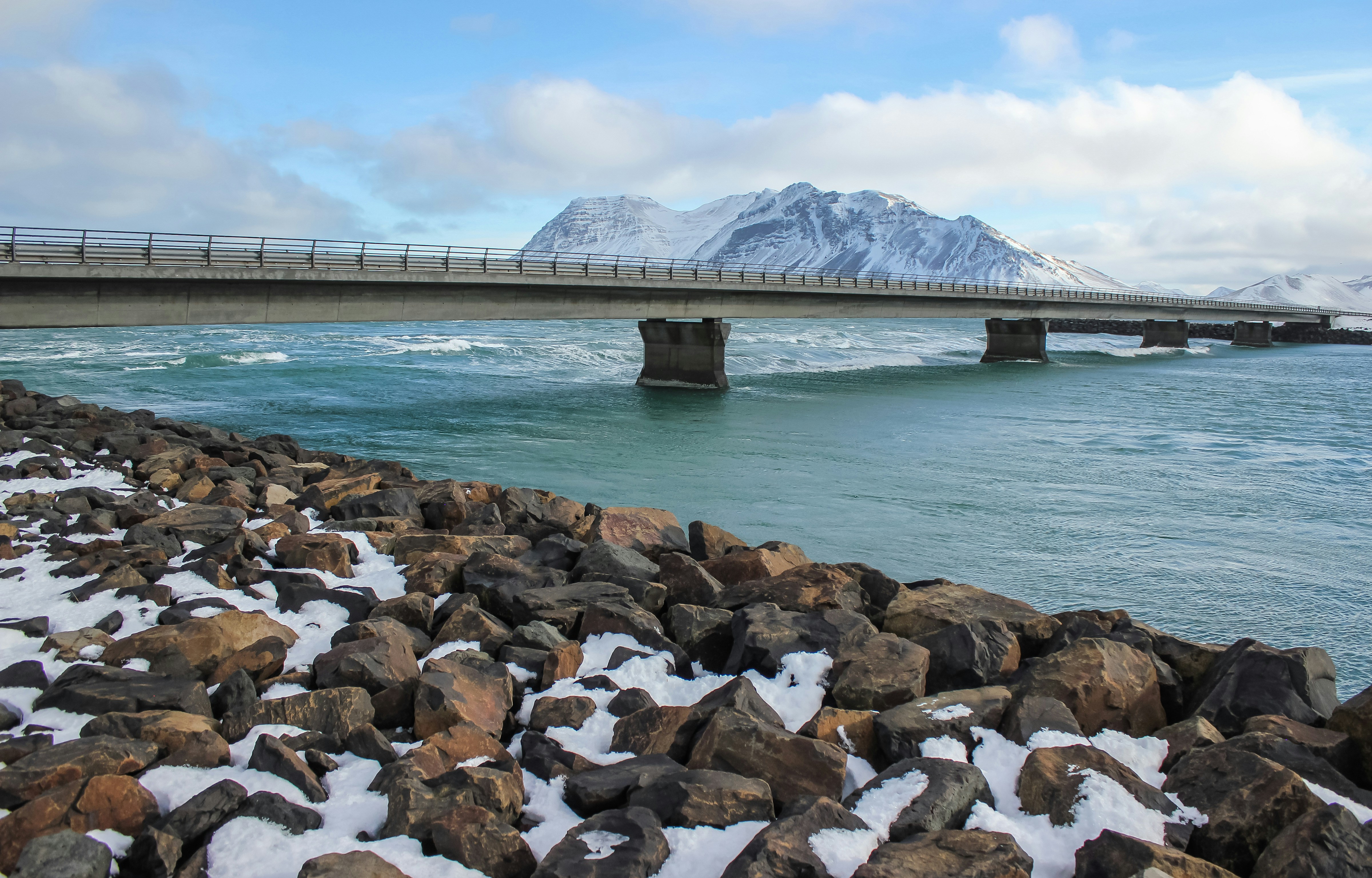 Bridge across Turquoise Fjord Beneath Snowbound Peaks