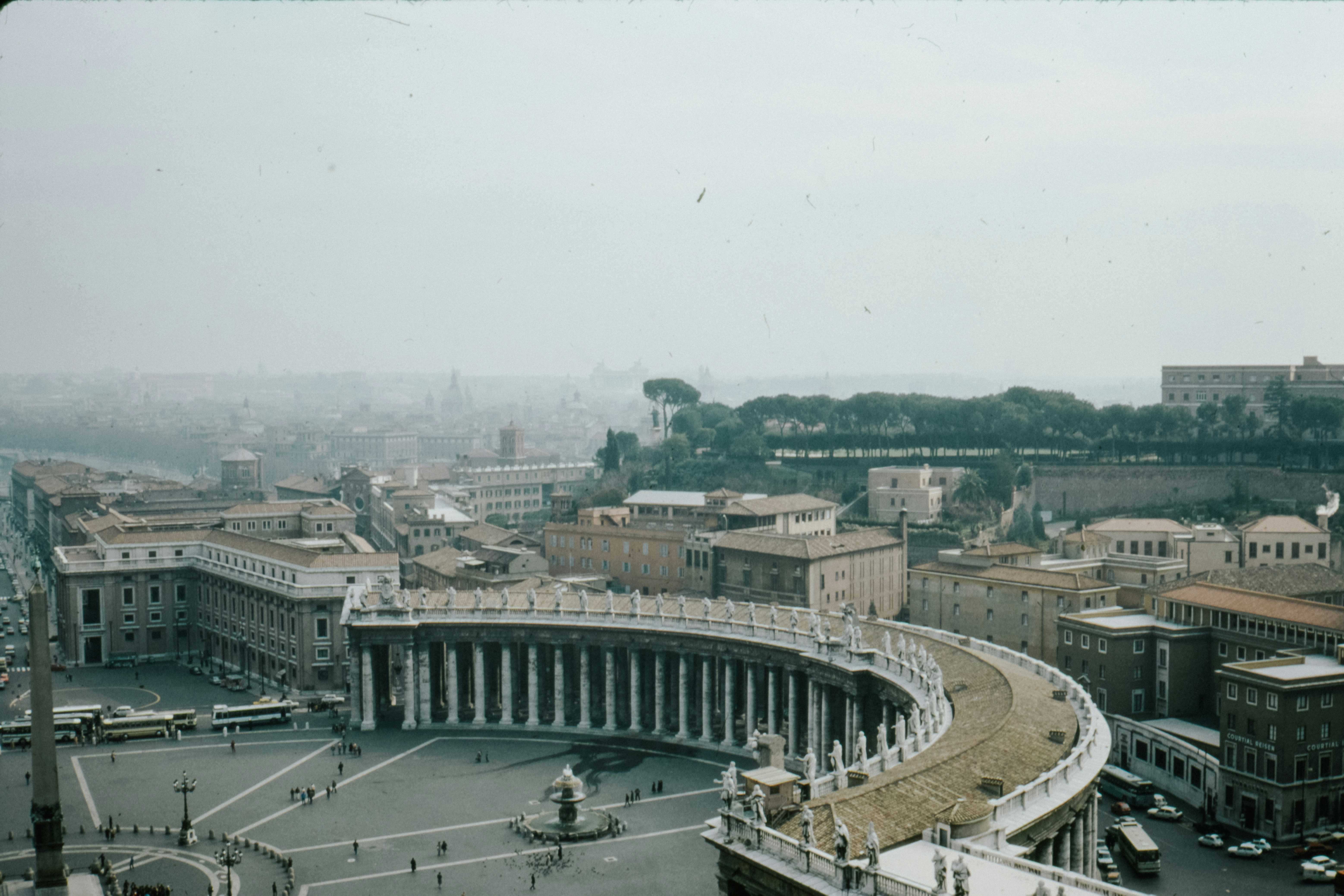 Aerial view of Vatican City showcasing the grand architecture of St. Peter's Basilica and the surrounding structures. The scene captures a blend of urban life and historical significance.