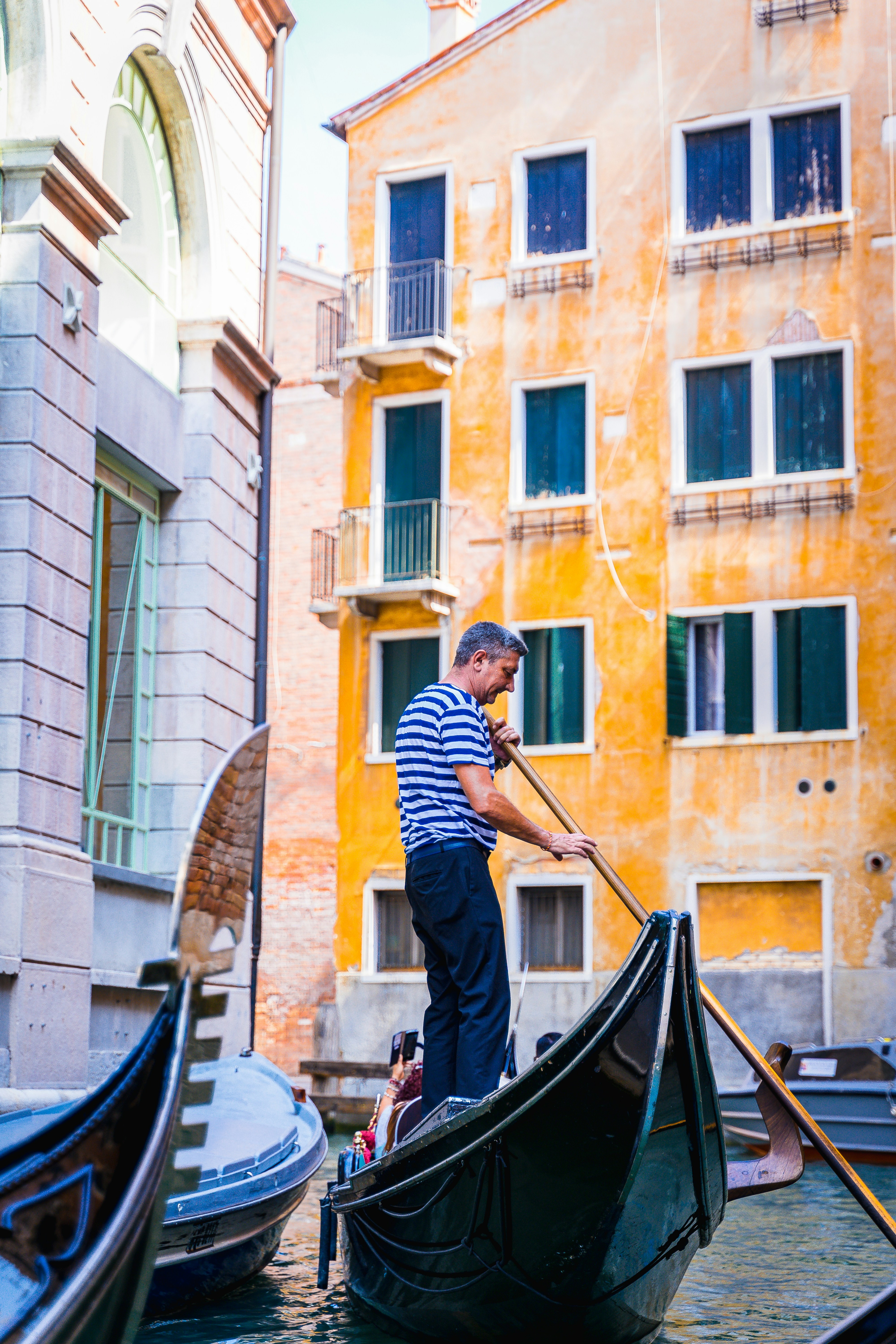 Stripes, Oars, and Orange Facades: A Gondolier on a Venetian Canal