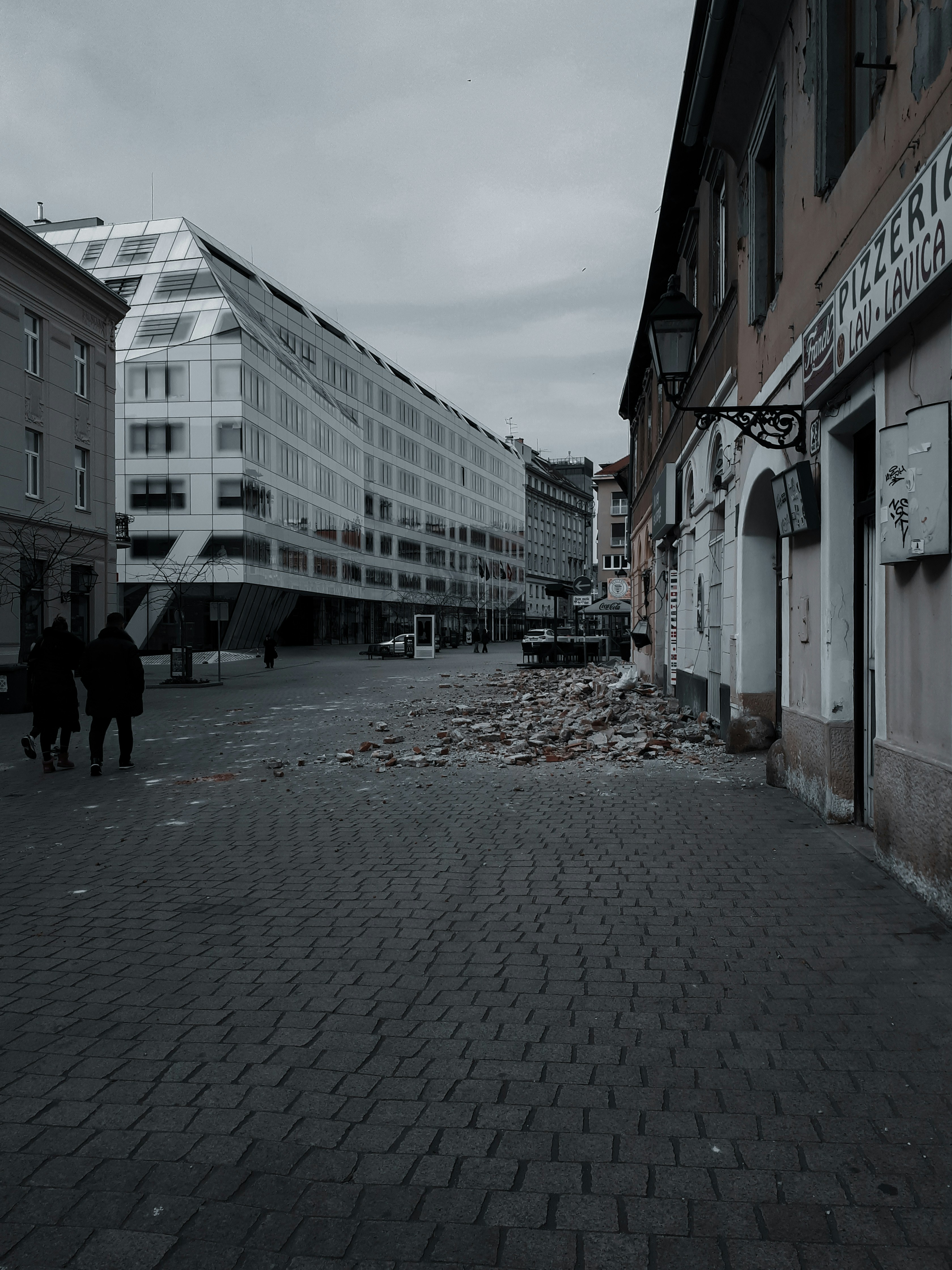 A street scene capturing the contrast between modern architecture and remnants of debris, highlighting urban transformation.