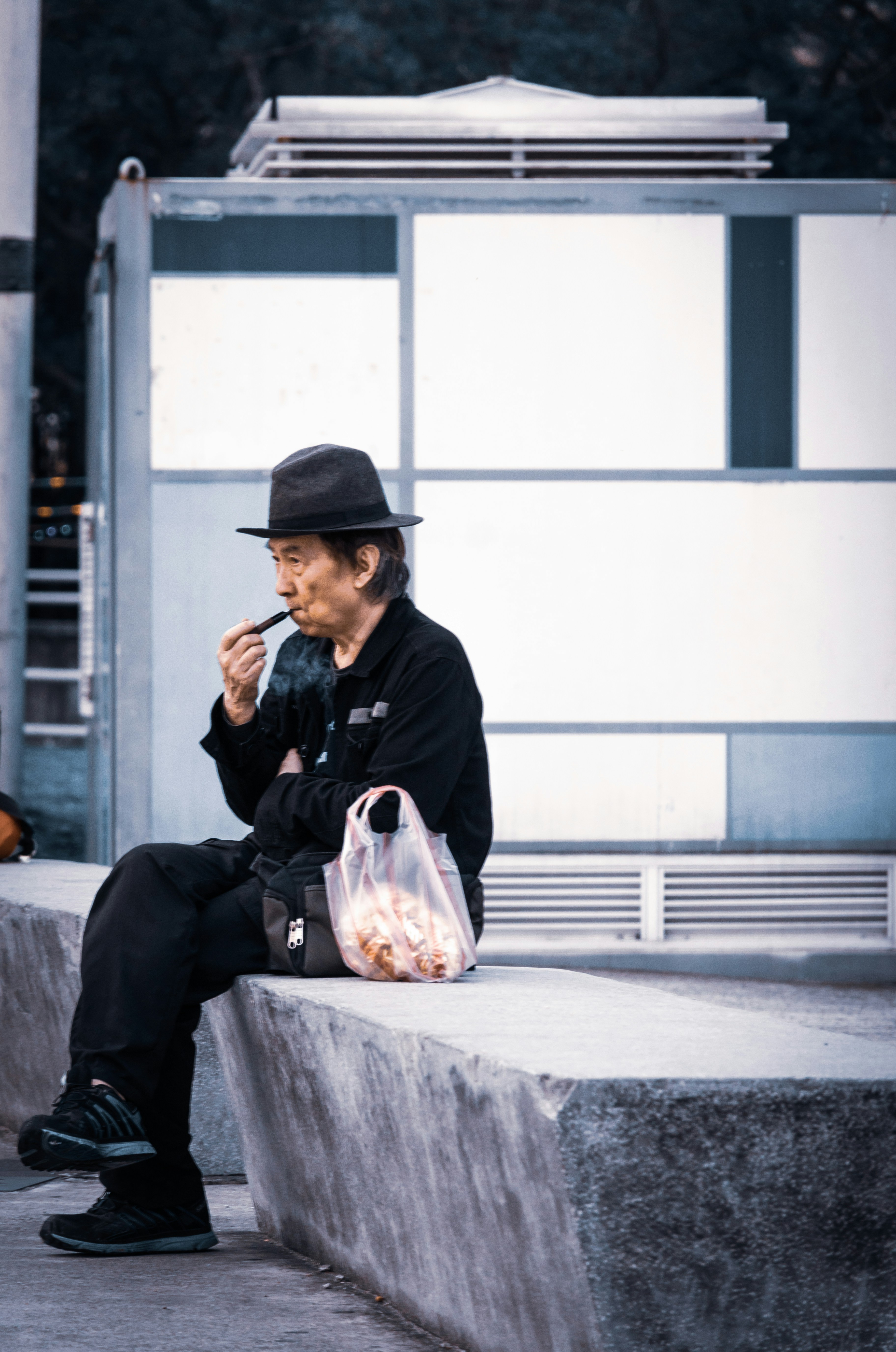 man in black jacket and black pants sitting on gray concrete bench