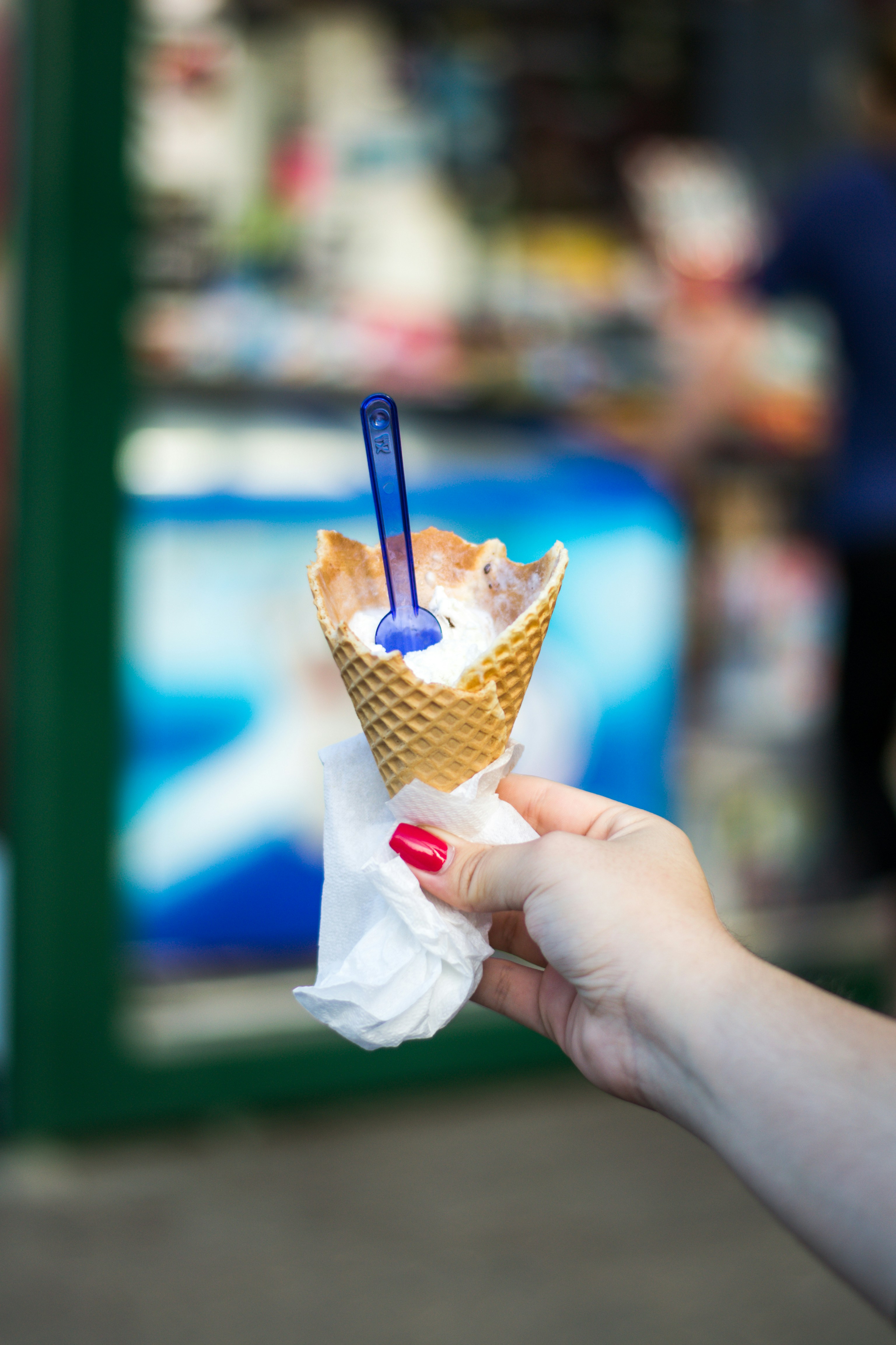 Blue Spoon in Focus: A Handheld Ice-Cream Cone Against City Blur