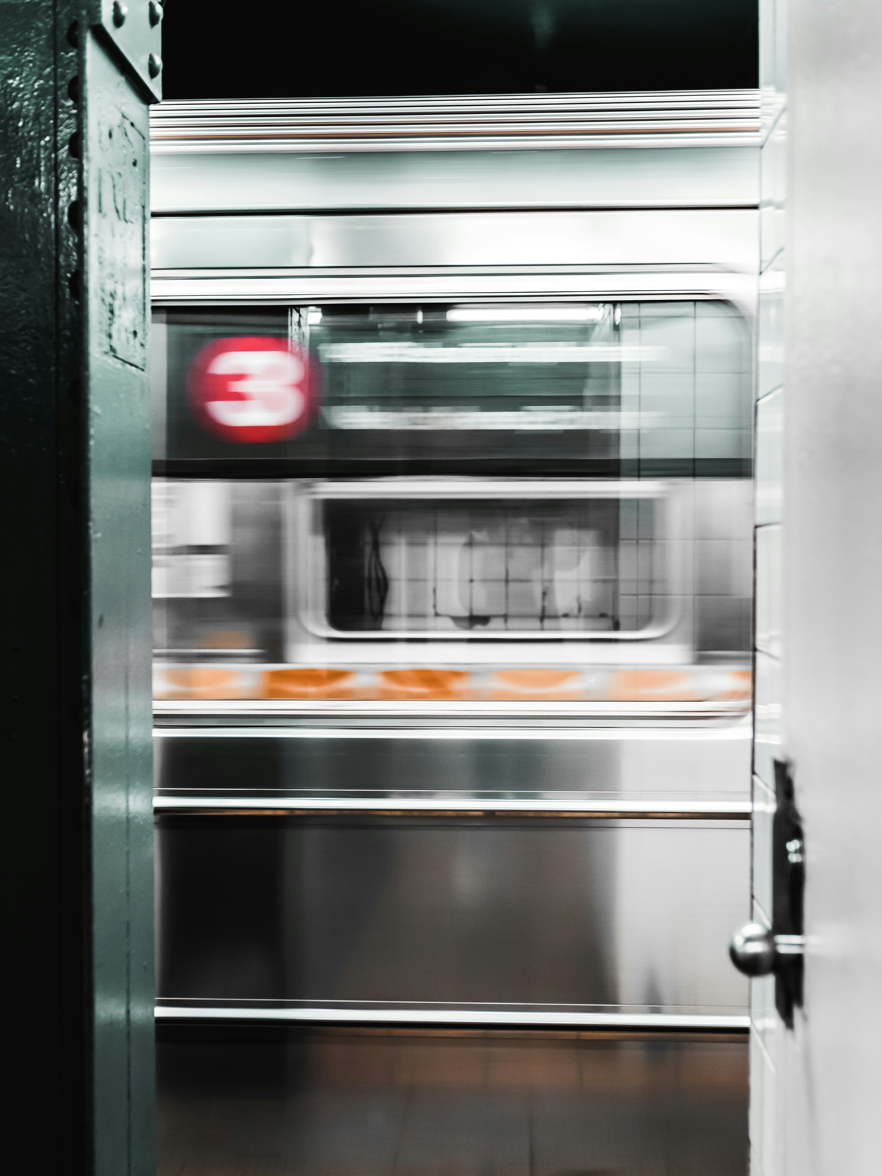 A subway train rushes past an open door, capturing the essence of city life in motion. The blurred motion conveys speed and urgency.