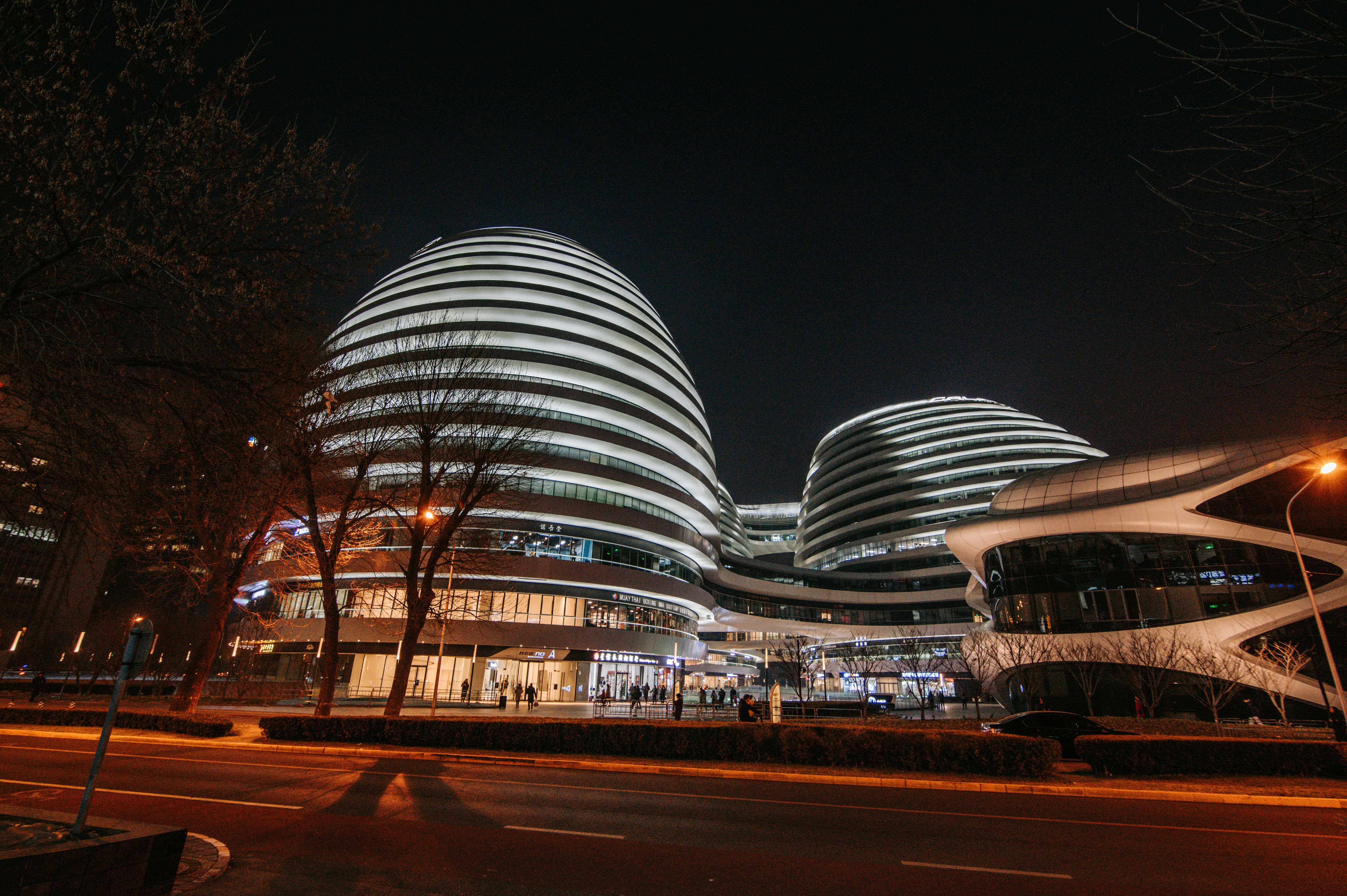Futuristic buildings with smooth, curved designs illuminated at night, showcasing innovative urban architecture.