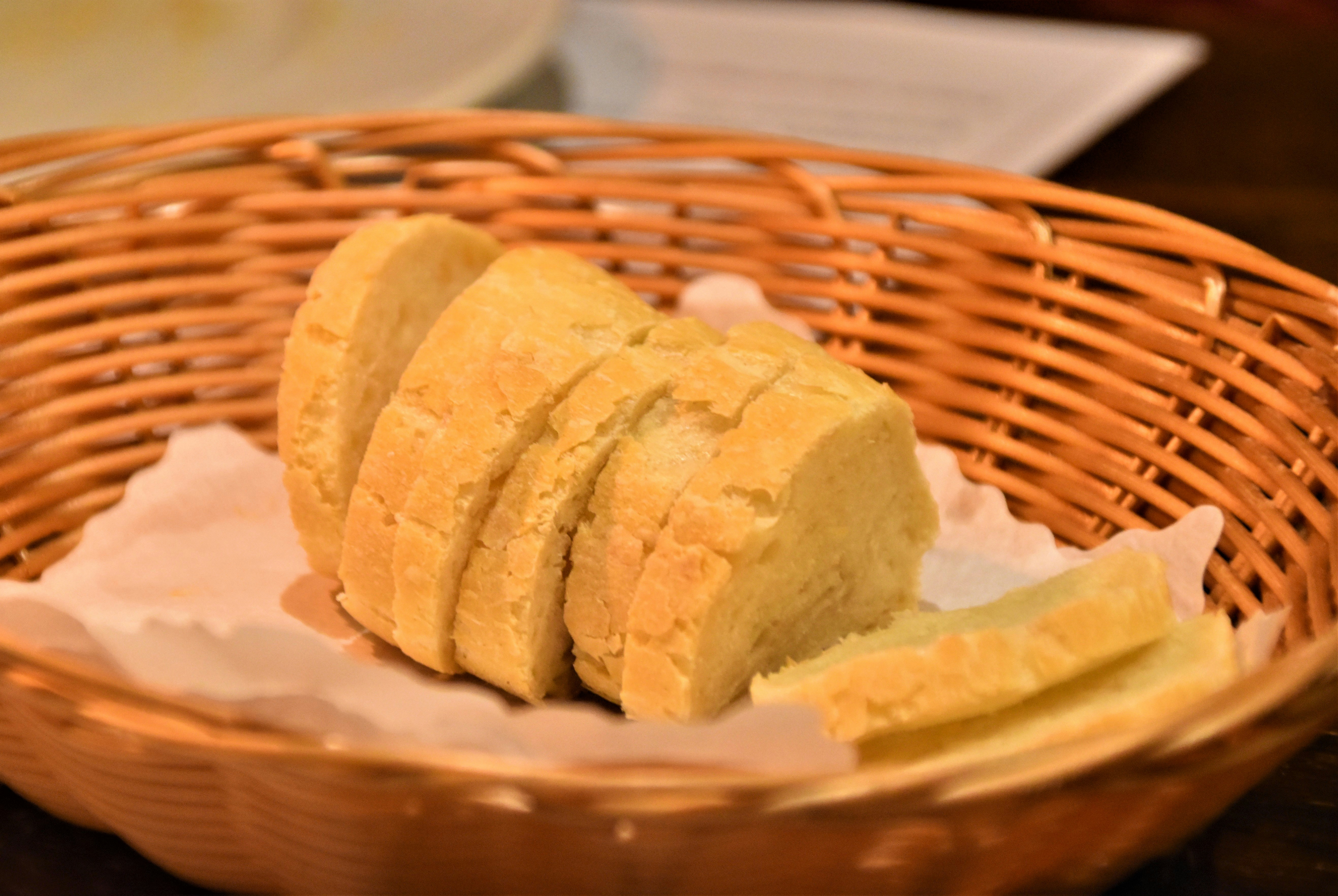 Freshly sliced artisan bread arranged in a woven basket, showcasing its crumbly texture and golden crust.