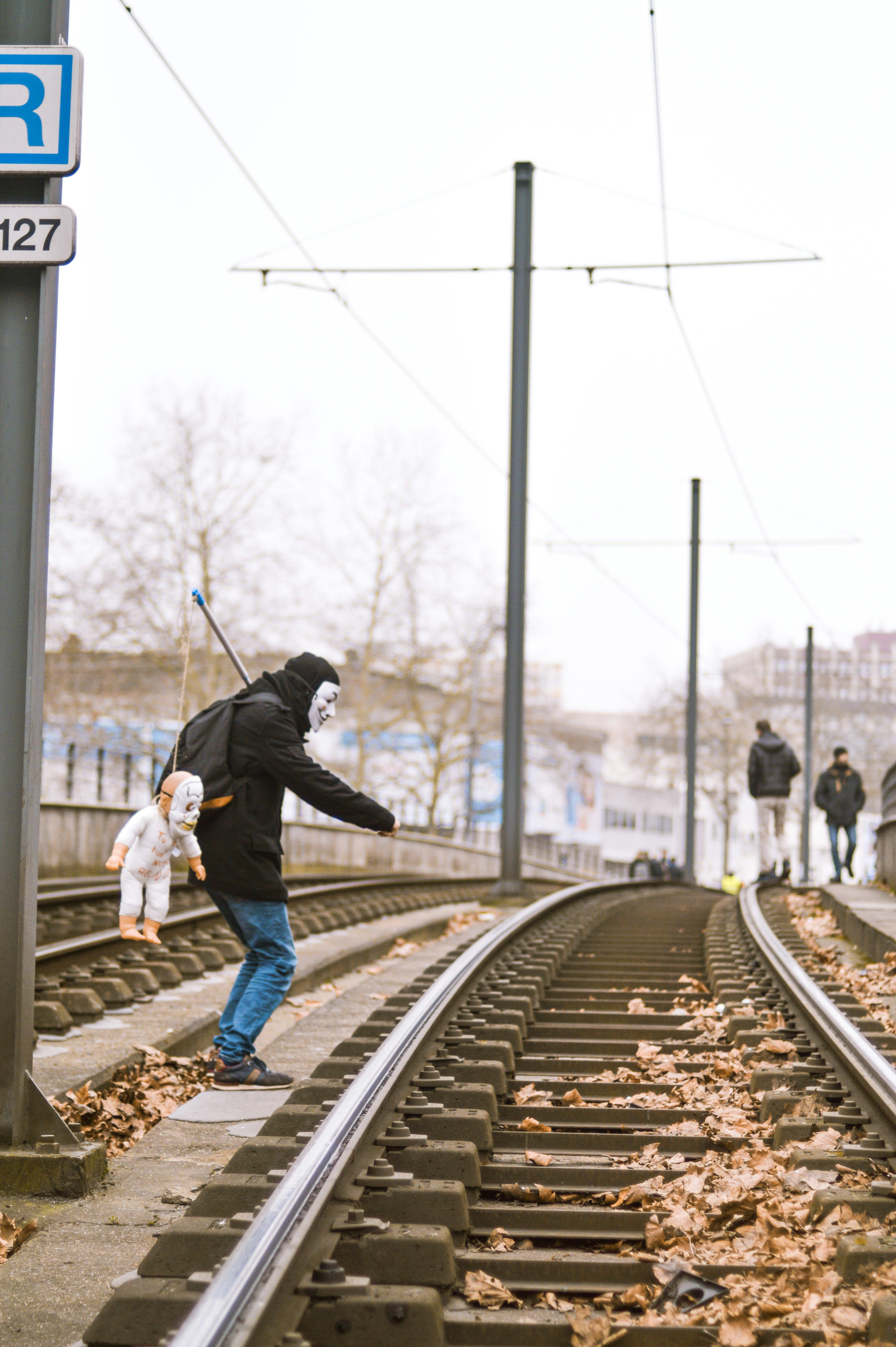 Man in black jacket and blue denim jeans standing on train rail during ...