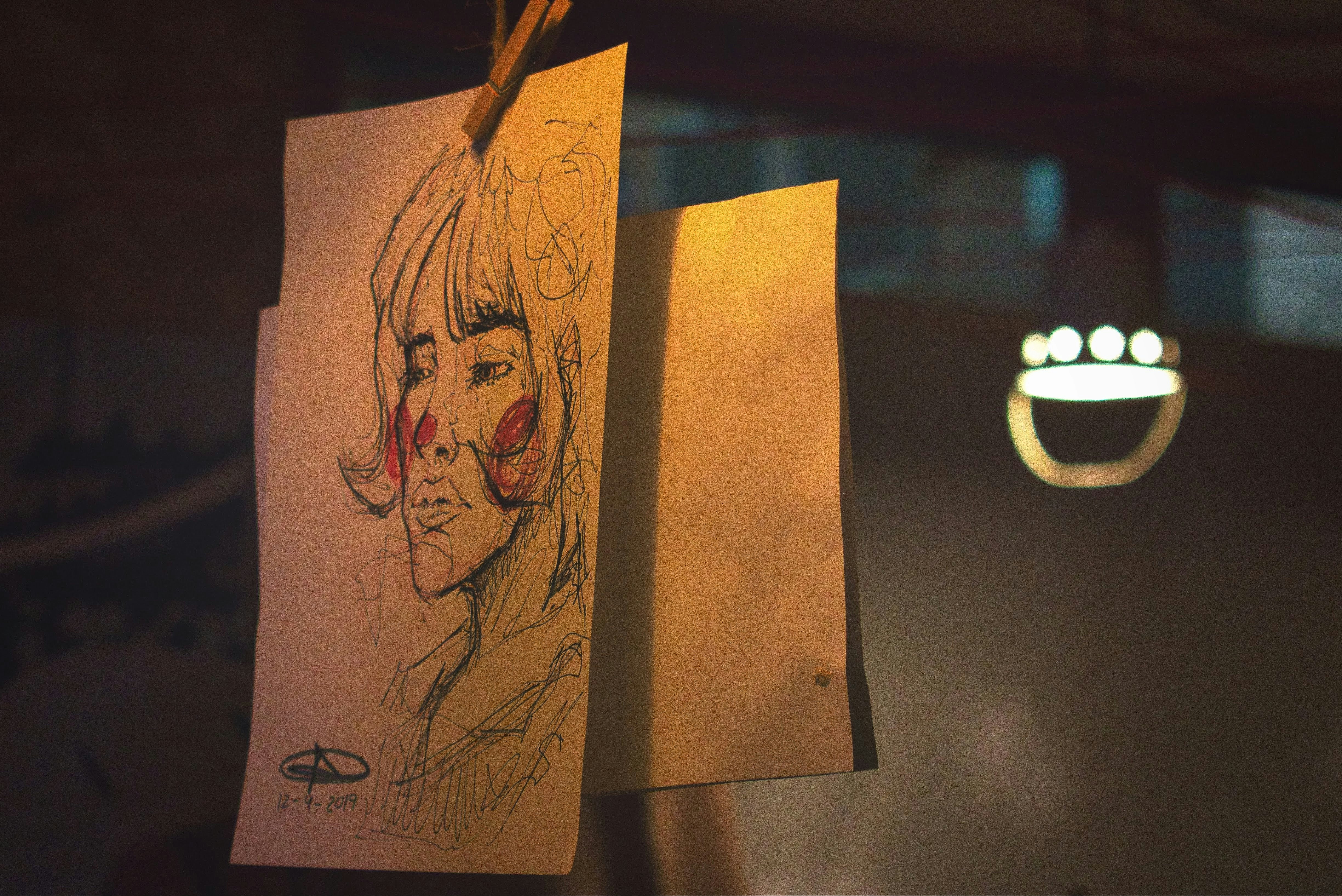 Sketch of a girl with rosy cheeks hanging on a line, illuminated by soft light in a rustic setting.