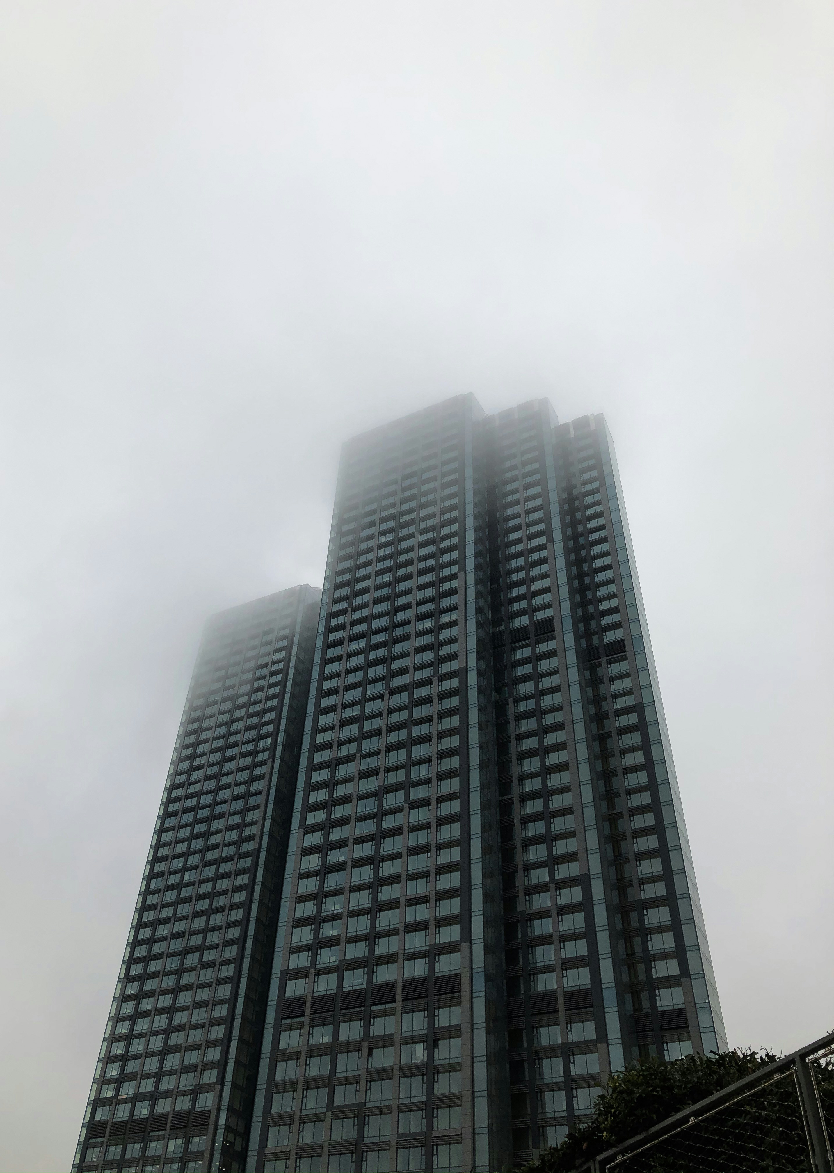Two towering skyscrapers partially obscured by fog, creating a mysterious urban atmosphere.