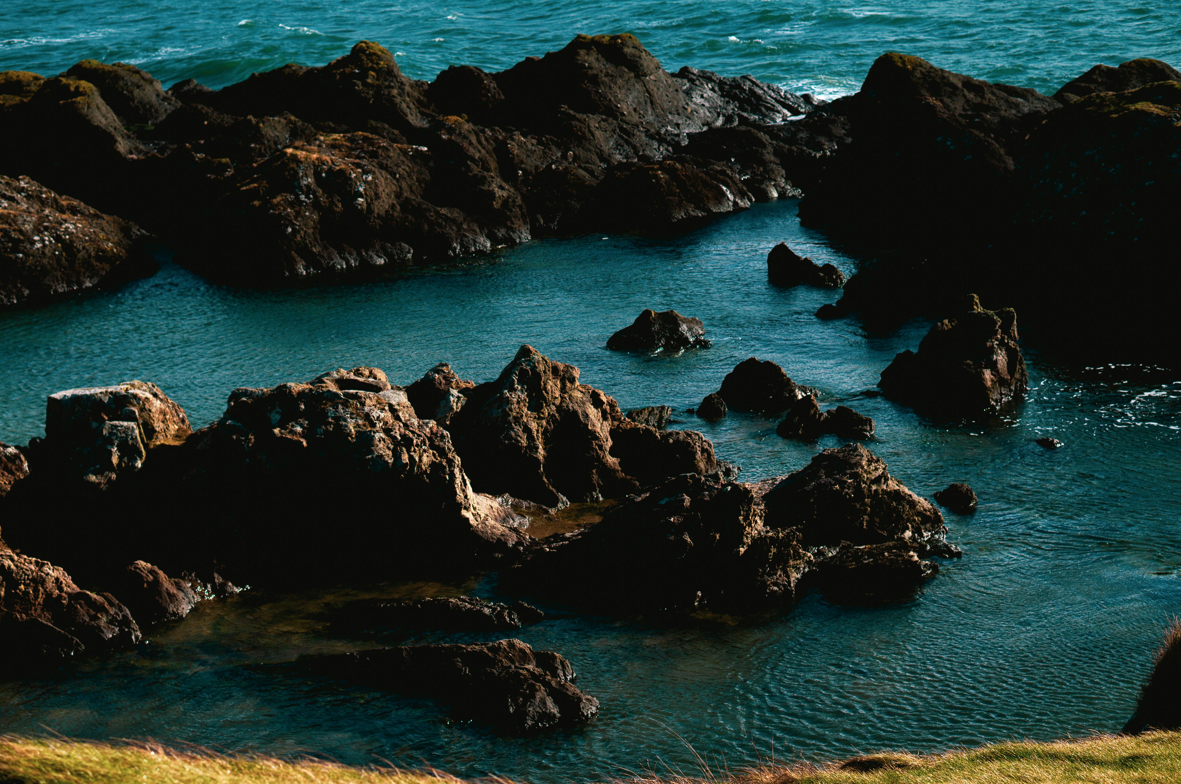 Black rock formation on body of water during daytime photo – Free ...