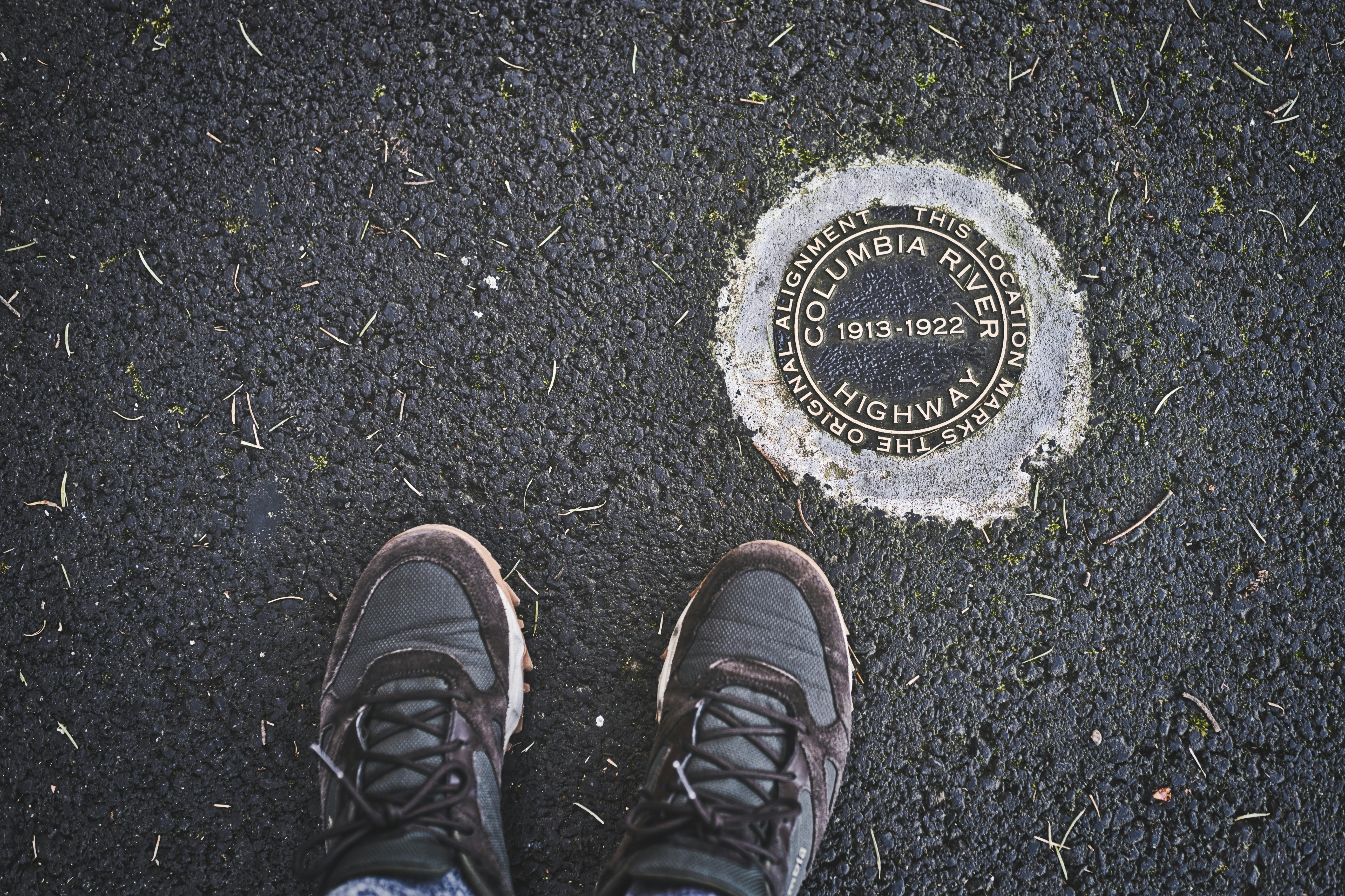 Old Columbia River Highway marker on the new State Trail.   Brass marker in asphalt with shoes.
