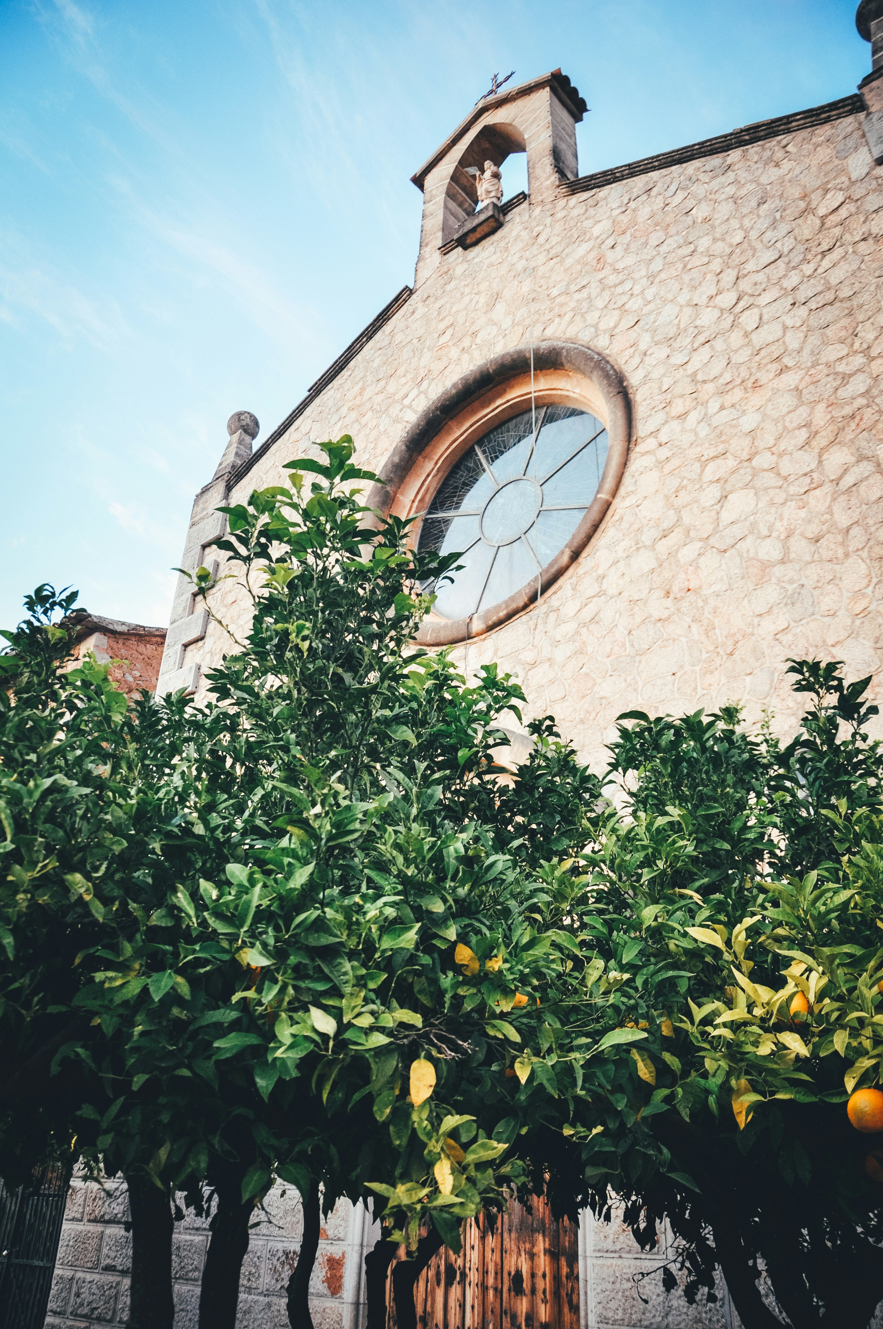 Rosette Above the Orchard: Sunlit Circular Window on a Stone Church