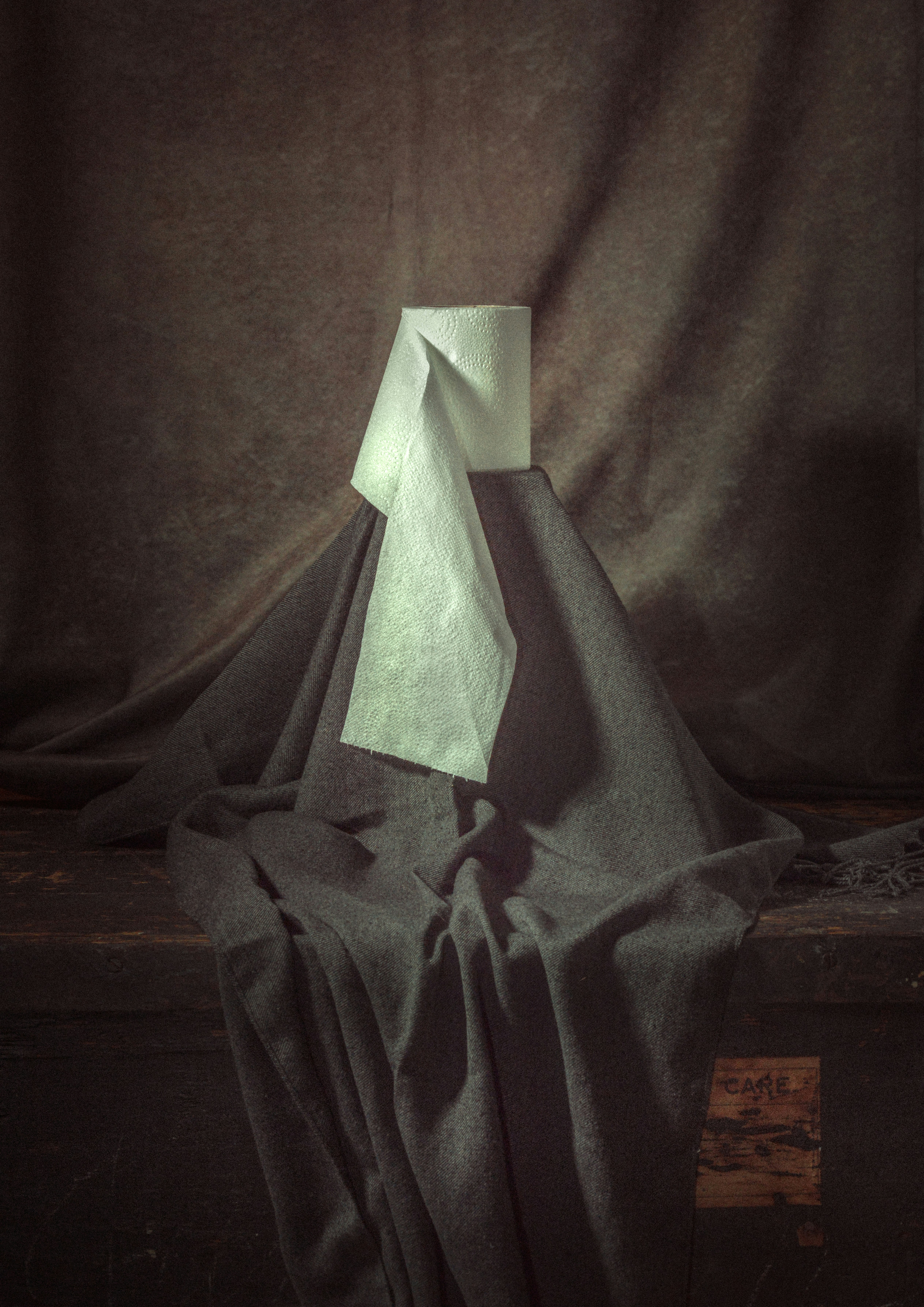 Abstract sculpture with sharp angles draped in soft, dark fabric against a muted backdrop.