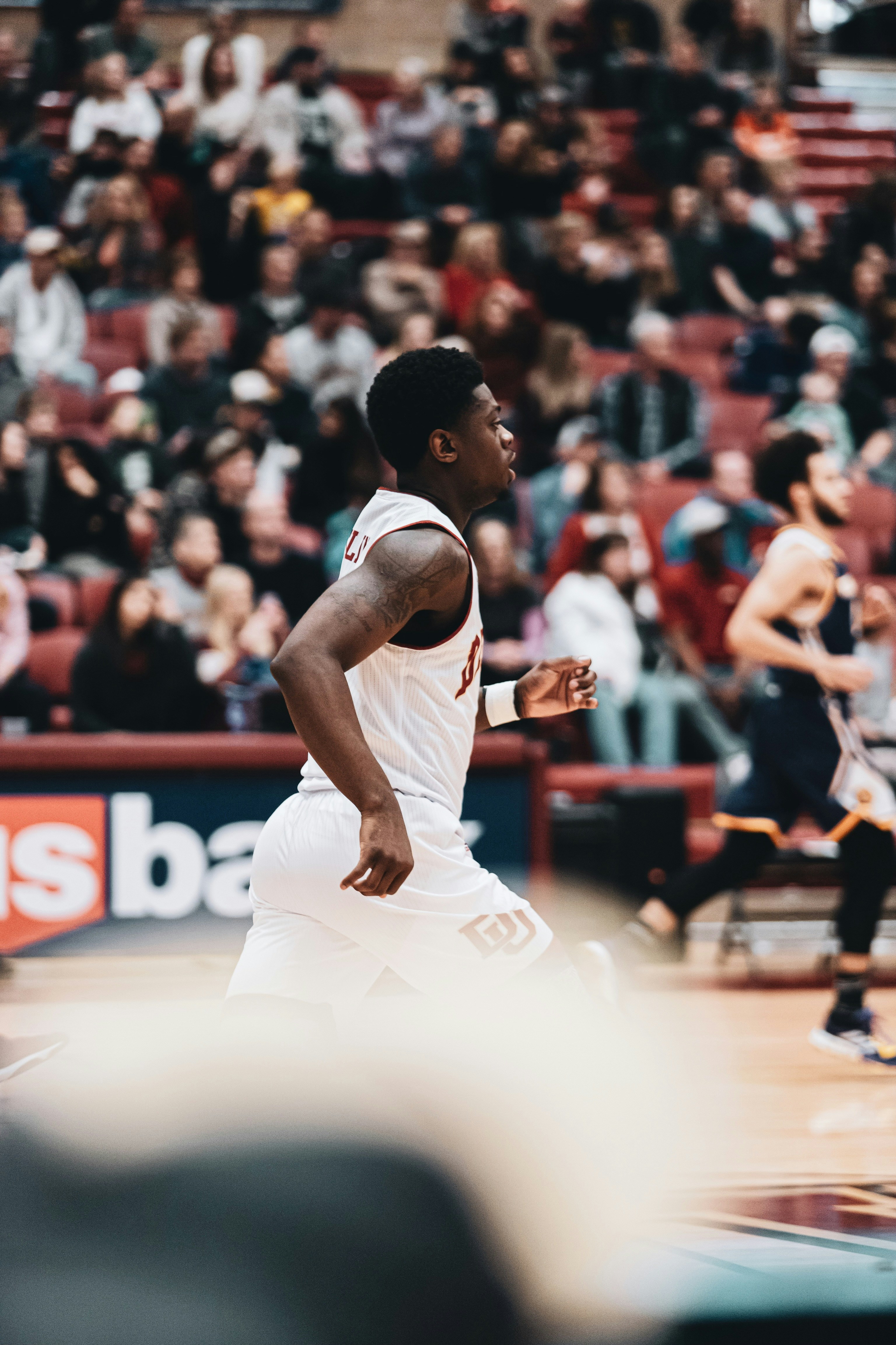 Momentum in White: A White-Jersey Guard Surges Through a Packed Arena