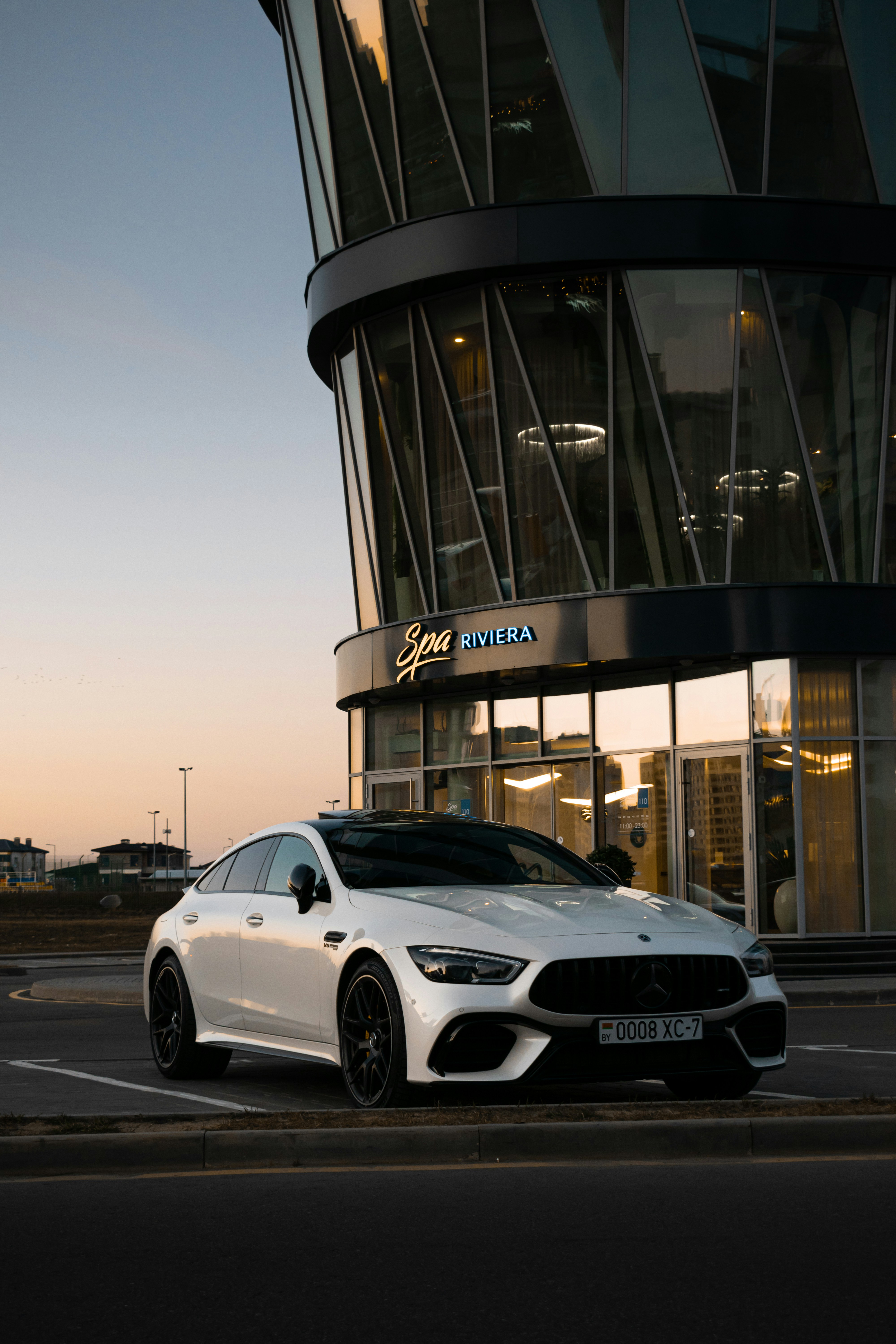Sleek white sports car parked in front of a contemporary glass building, showcasing a blend of luxury and modern design.