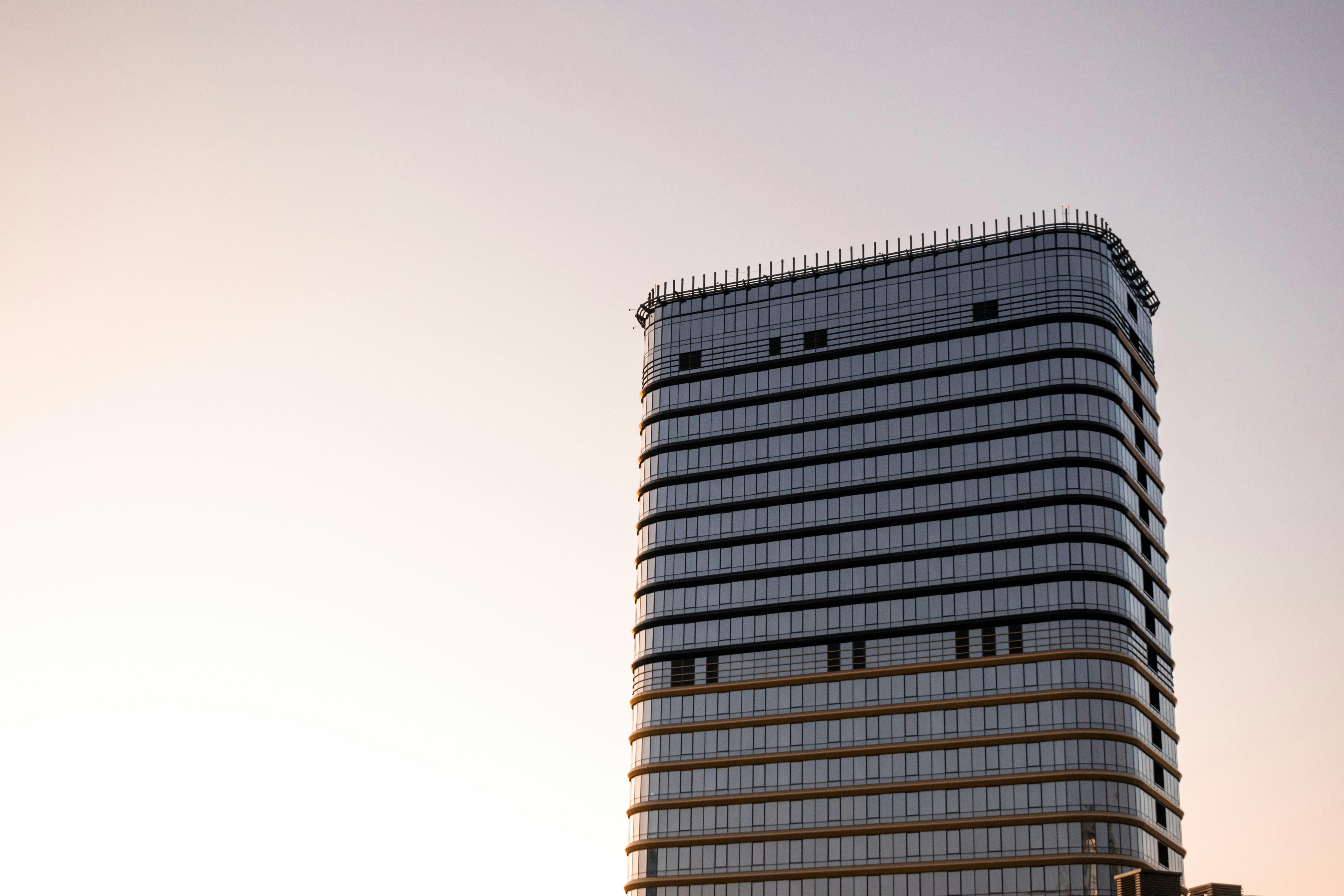 Modern high-rise with horizontal stripes against a soft evening sky.