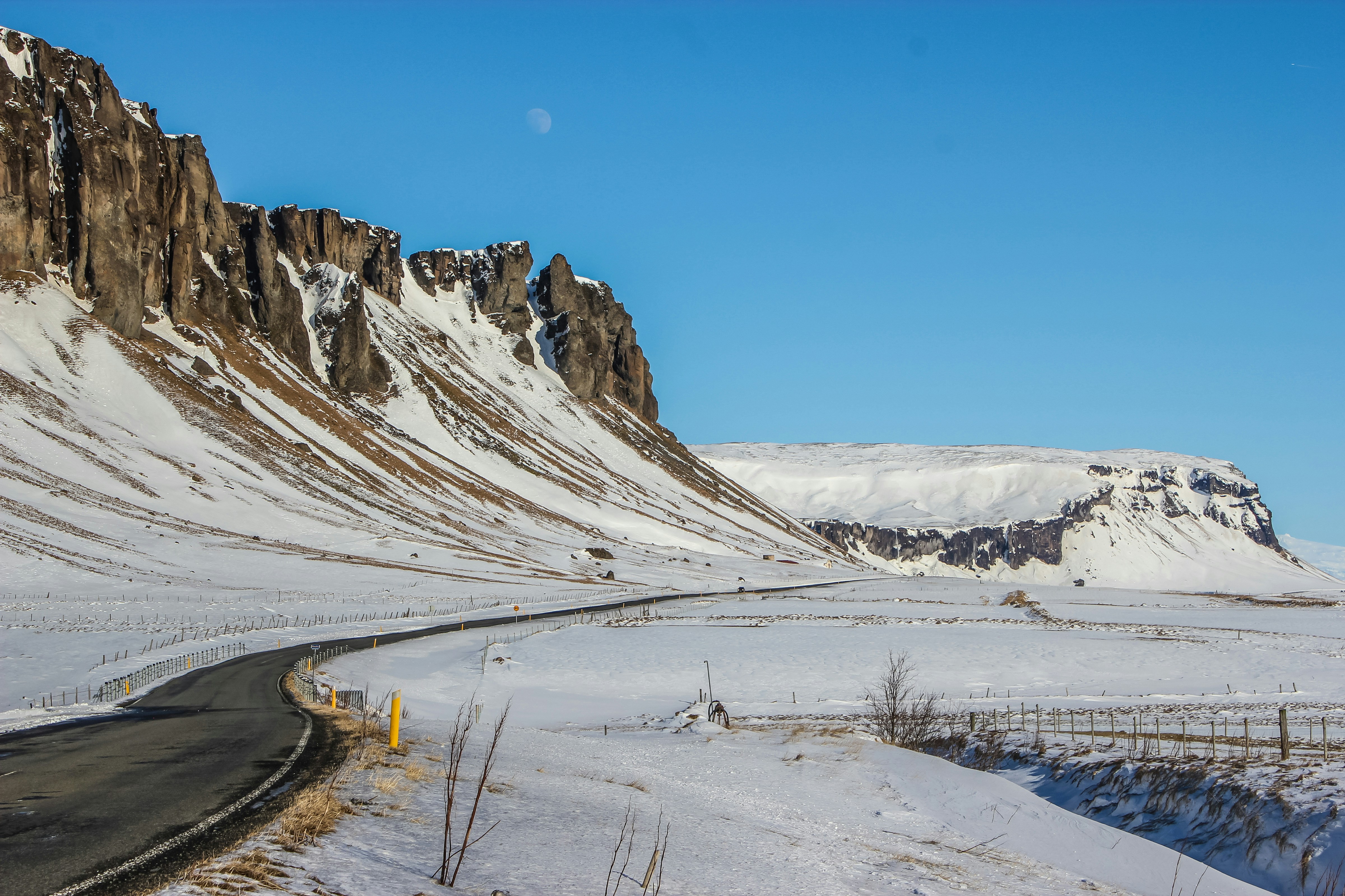 Snowbound Curves: A Lone Road Winding Beneath Cliffs