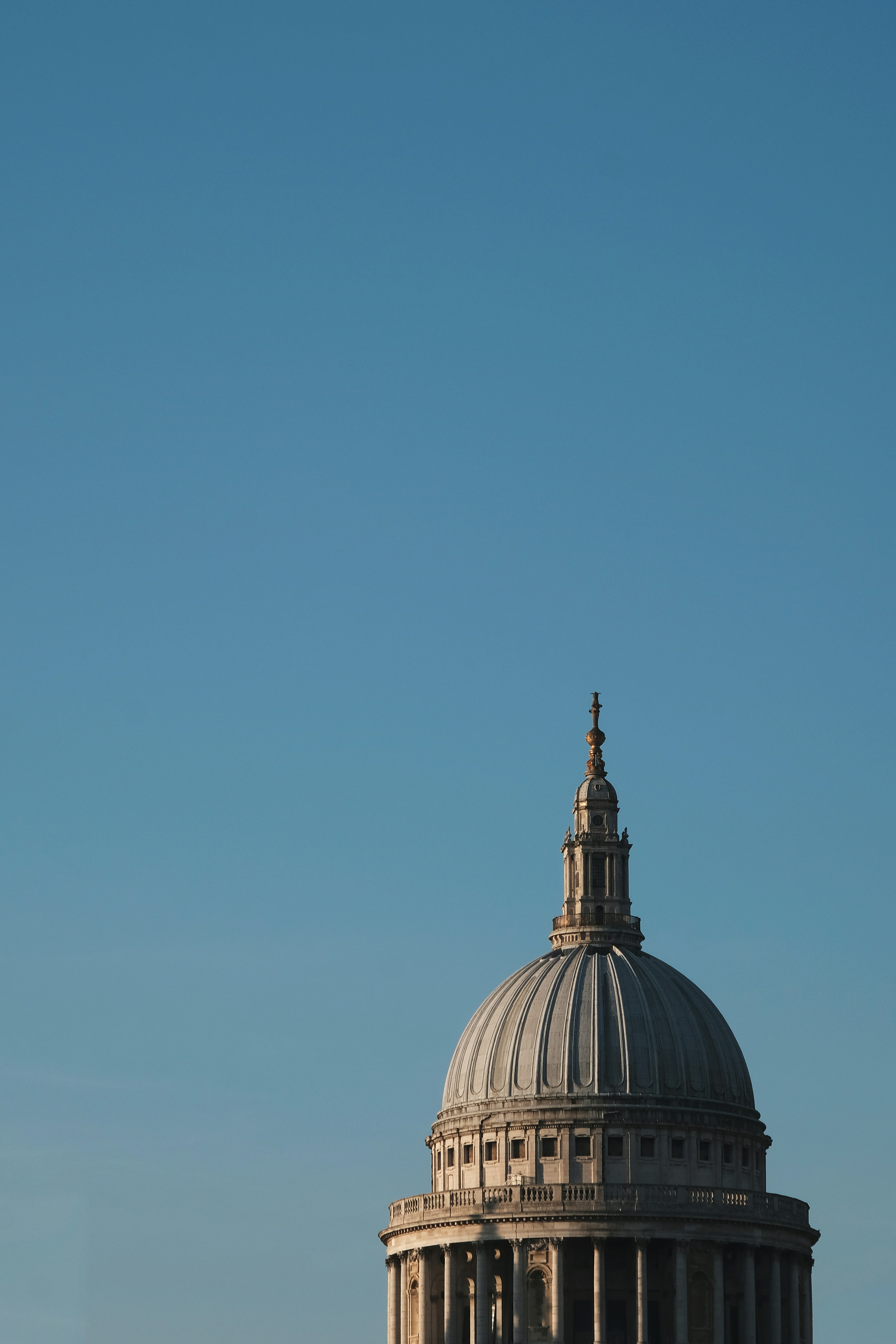 The iconic dome of St. Paul's Cathedral rises against a clear blue sky, showcasing intricate architectural details and grandeur.
