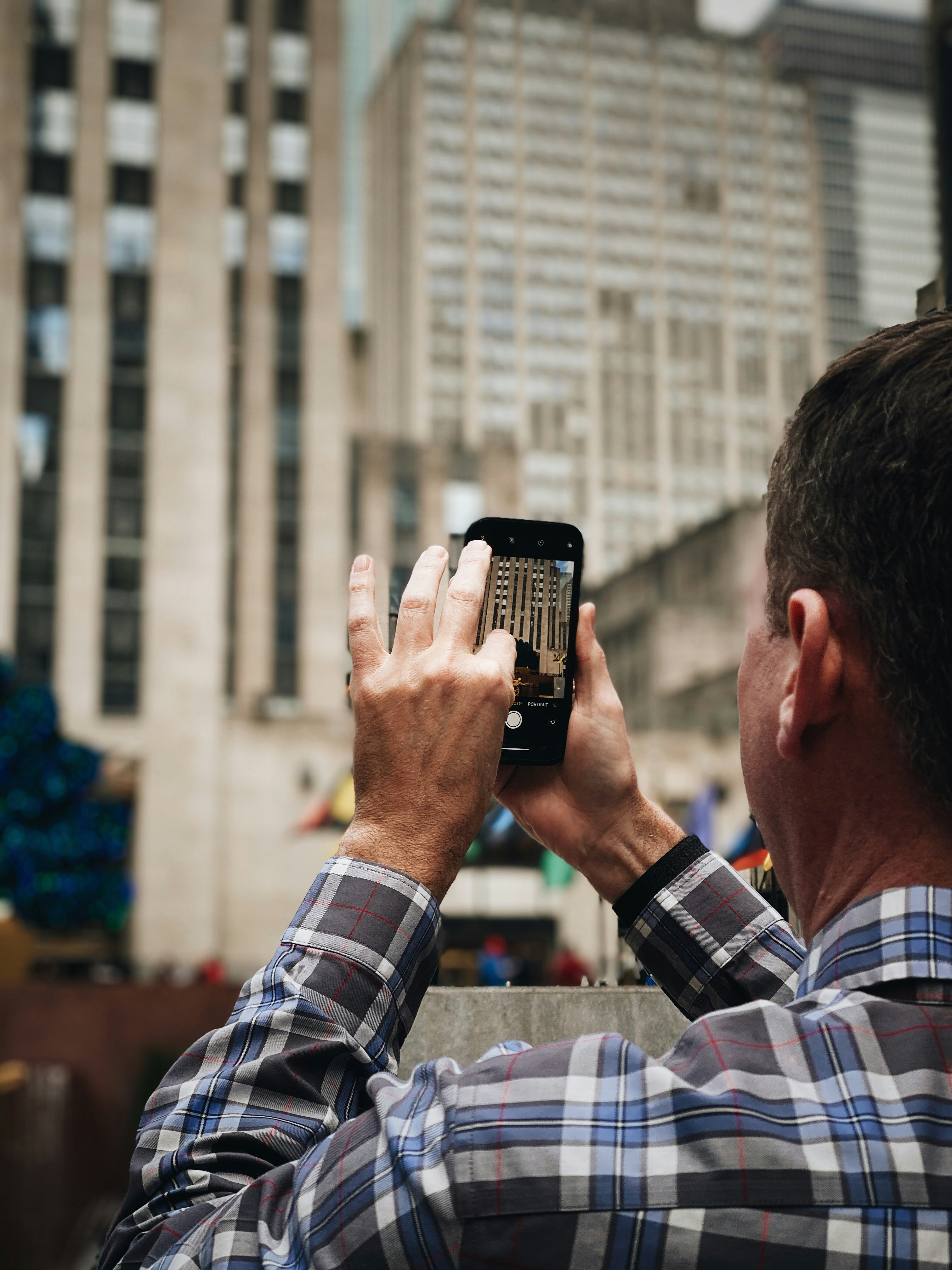 Man in white red and blue plaid dress shirt holding black qwerty phone ...