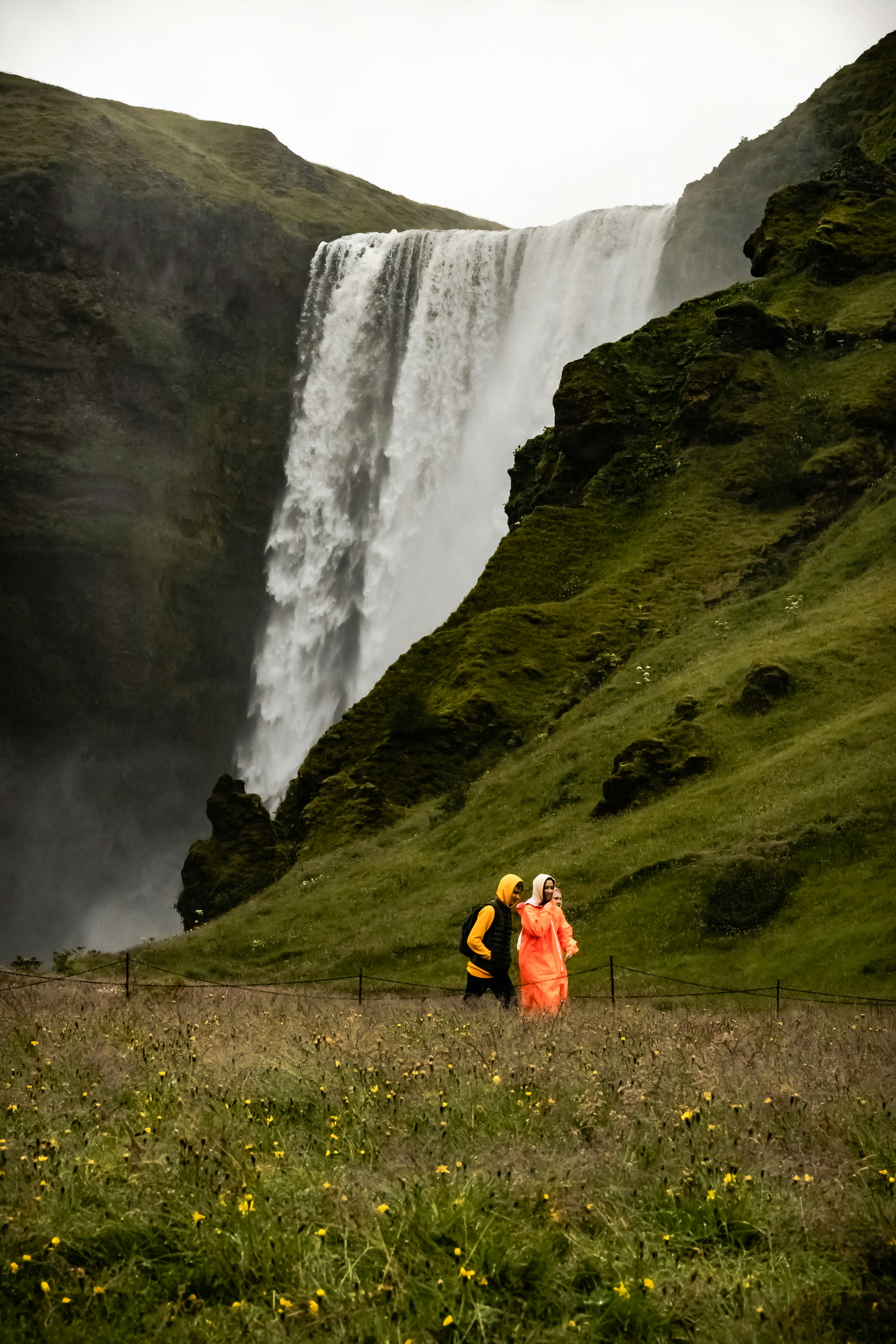 Two Hikers near a Majestic Waterfall in a Verdant Gorge