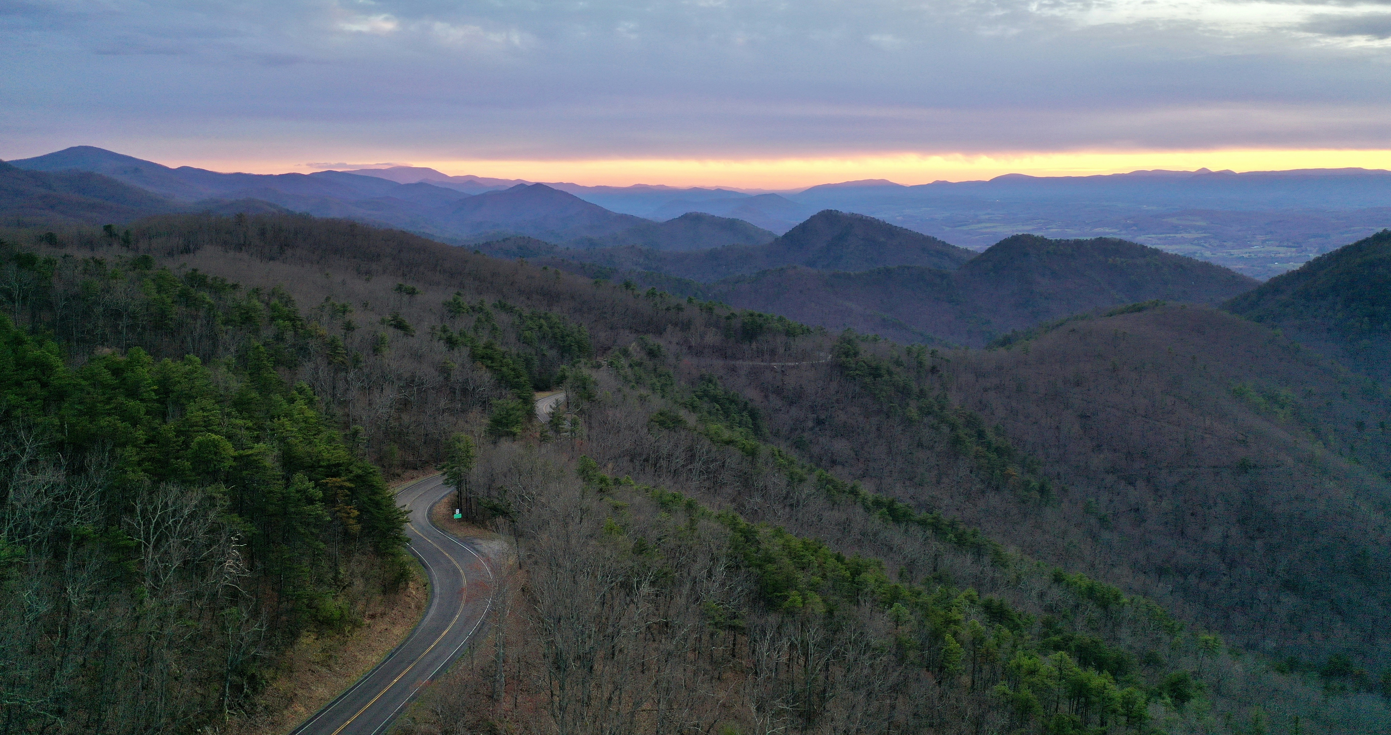 Winding road through the Blue Ridge Mountains under a colorful sunset sky.
