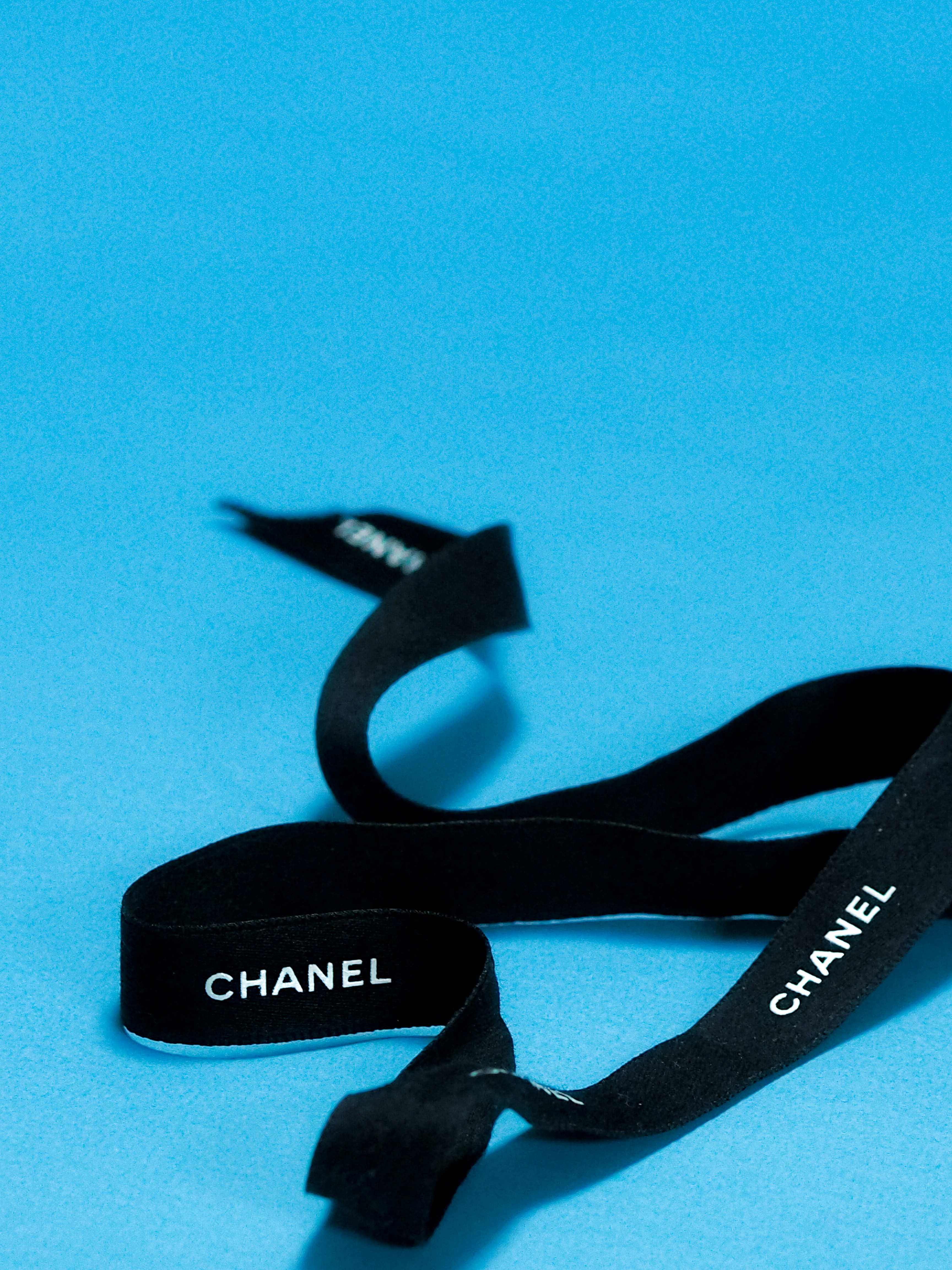 Black Chanel Ribbon Untwined on a Bright Blue Studio Backdrop