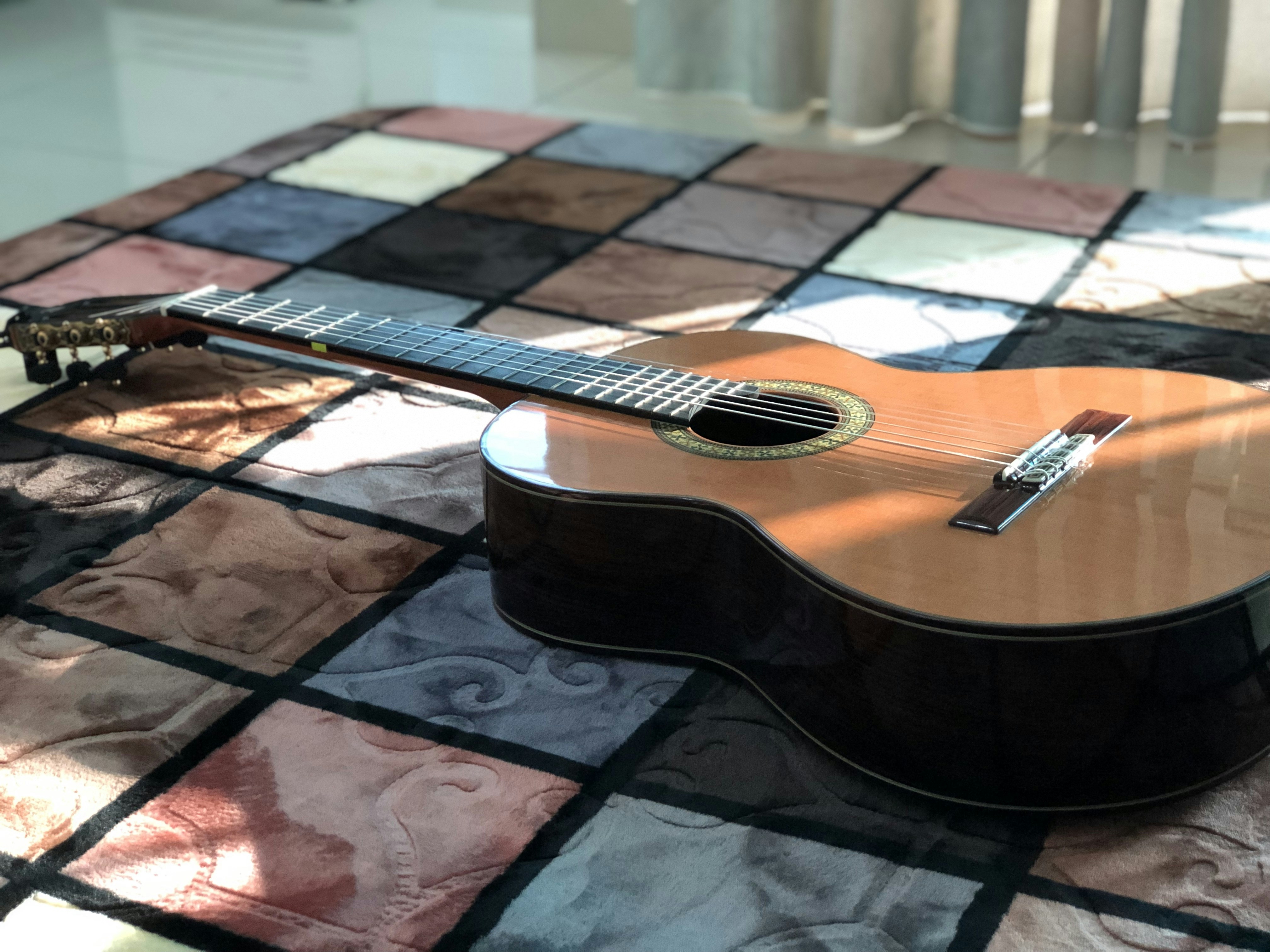 Sunlit Acoustic: A Guitar Resting on a Patchwork Rug