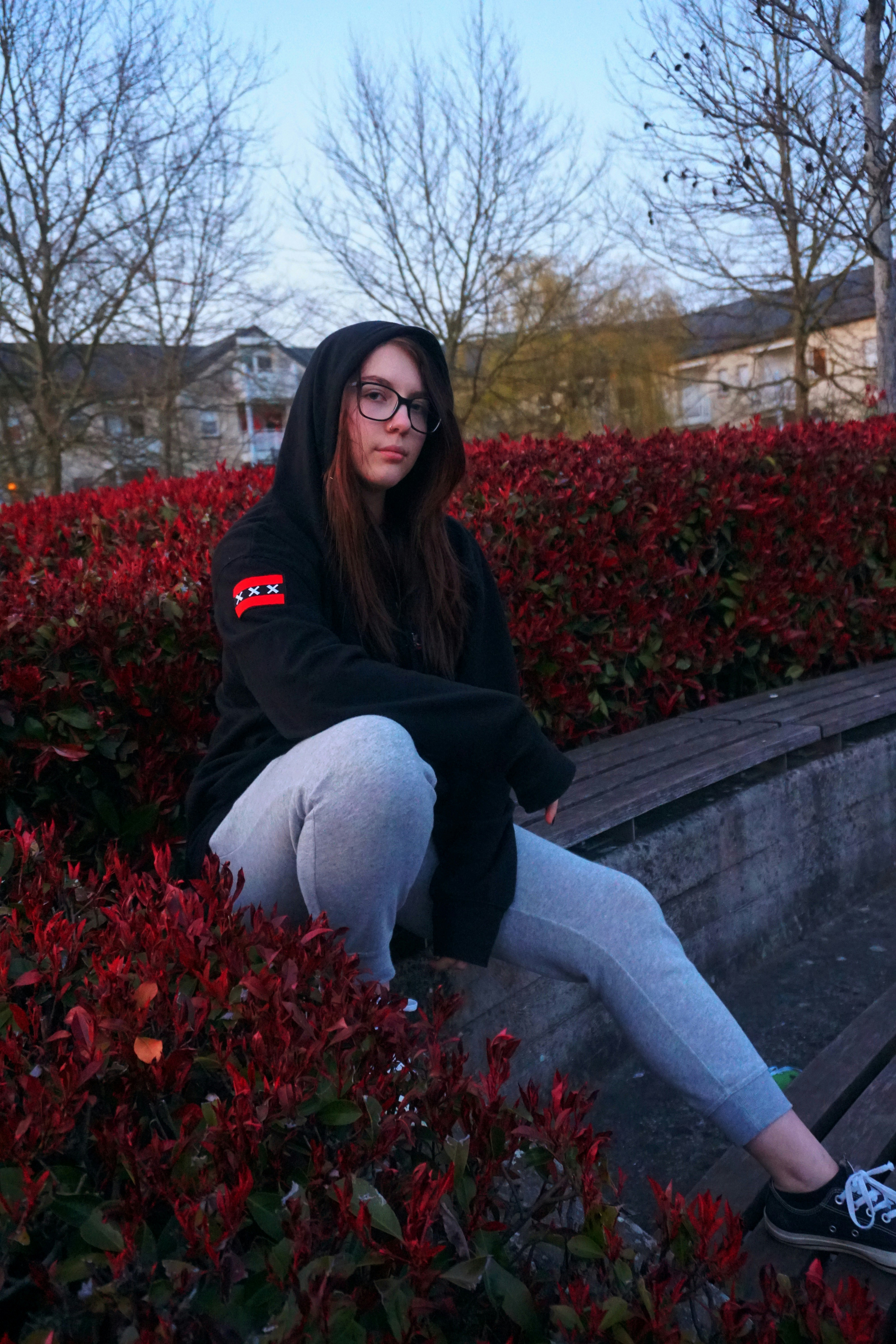 woman in black hoodie and gray pants sitting on gray concrete bench