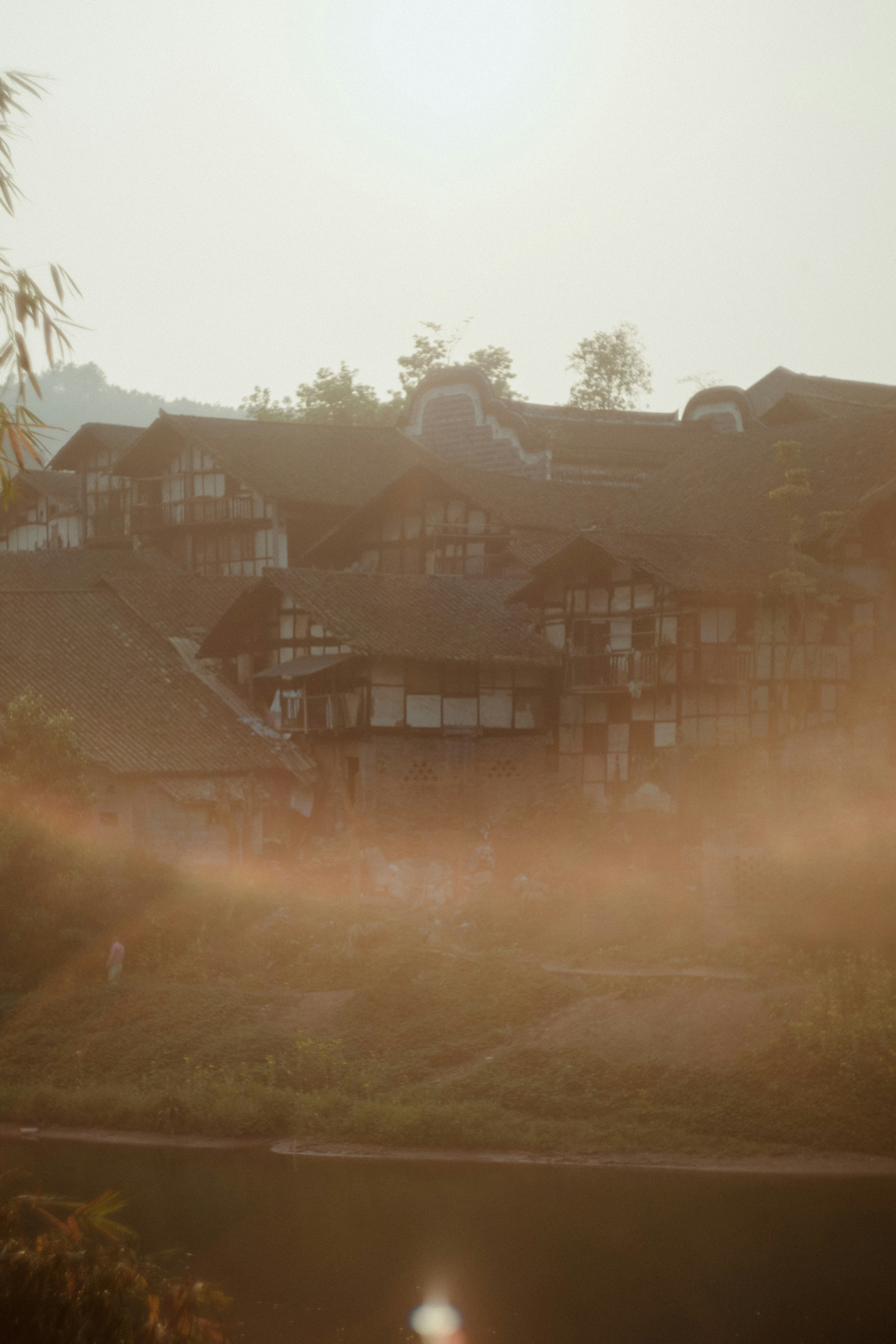 Foggy riverside village bathed in warm sunset haze