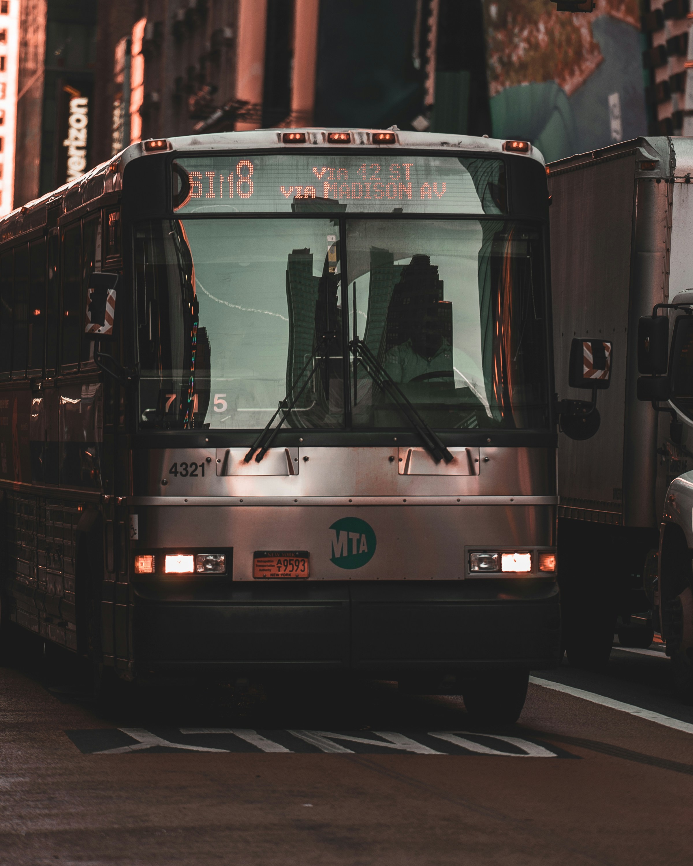 Neon Heat and Steel: Front View of an MTA Bus in Night Traffic