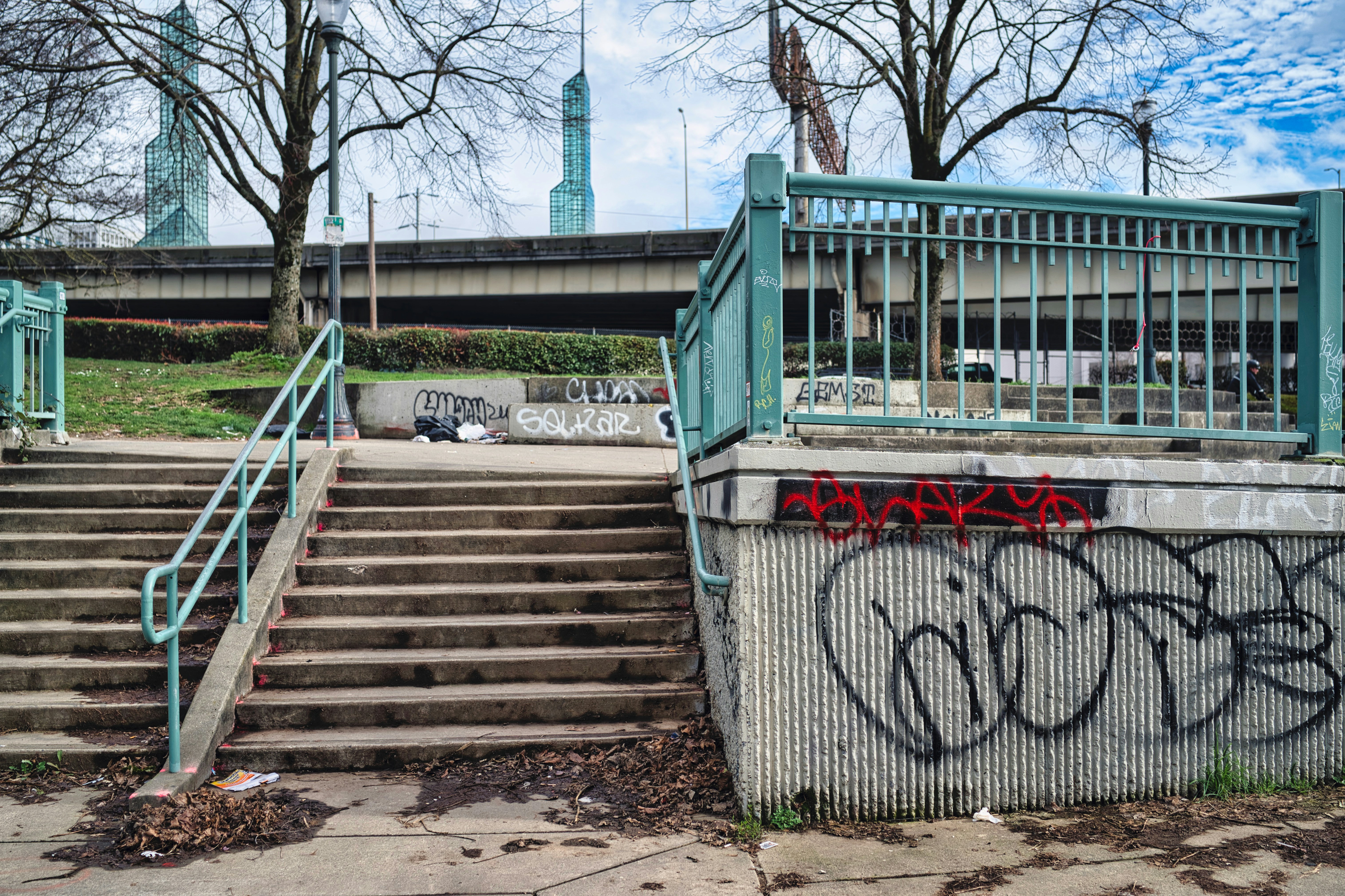 Teal Railings Framing a Graffiti-Streaked Urban Staircase Under the Overpass