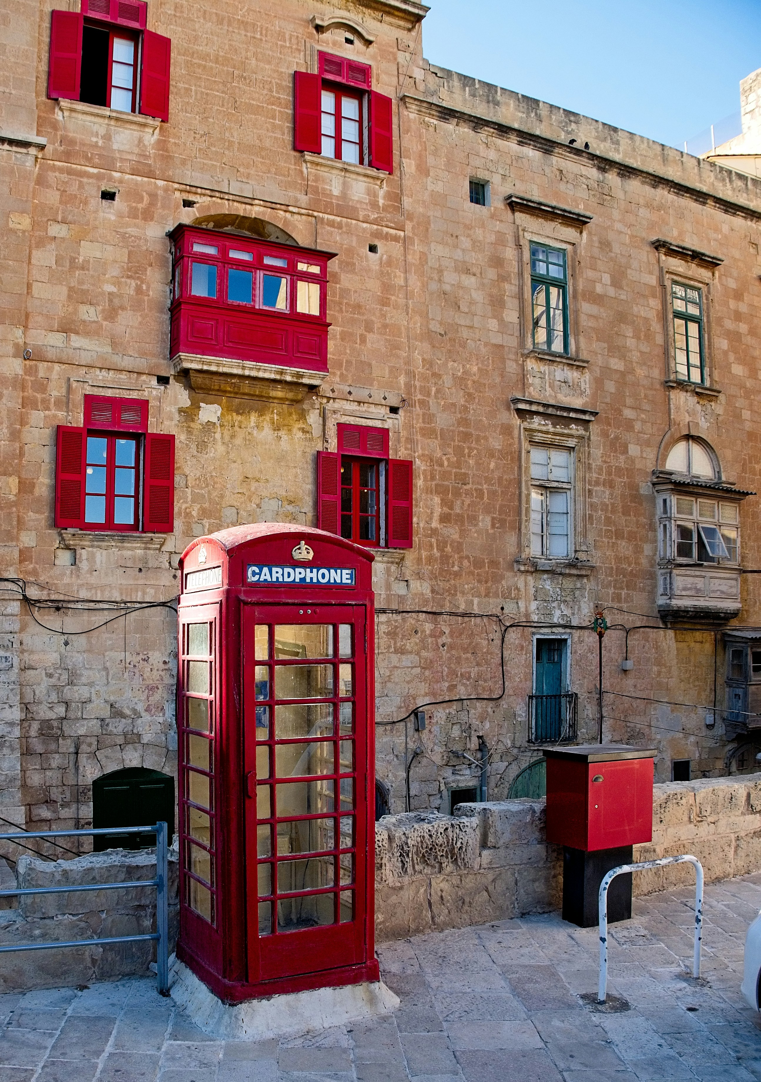 Red telephone booth near brown concrete building during daytime photo ...